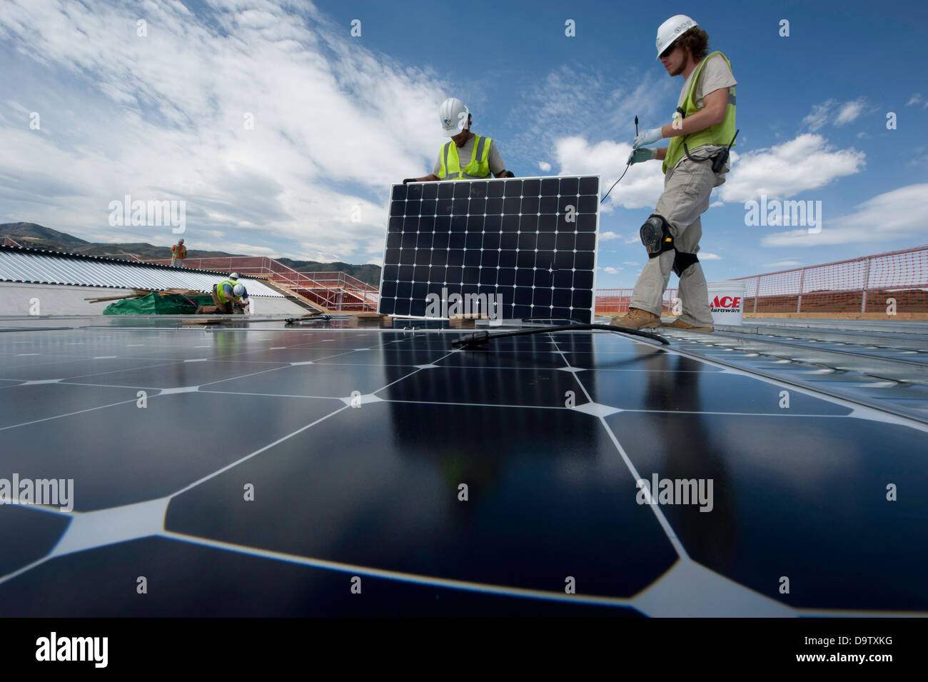 Construction workers install photovoltaic solar electric panels on the ...