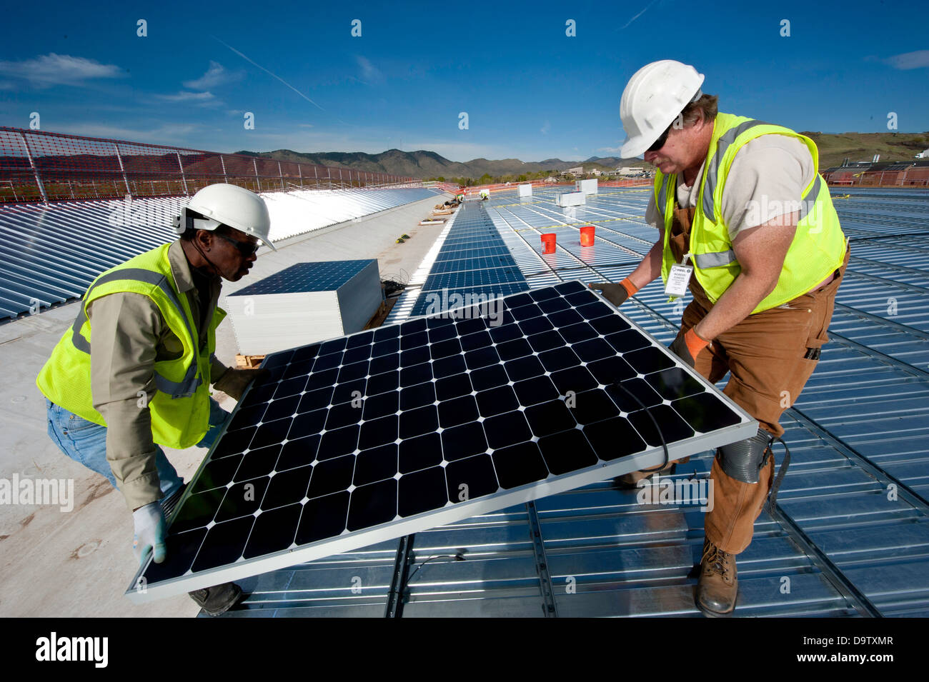 Construction workers install photovoltaic solar electric panels on the ...
