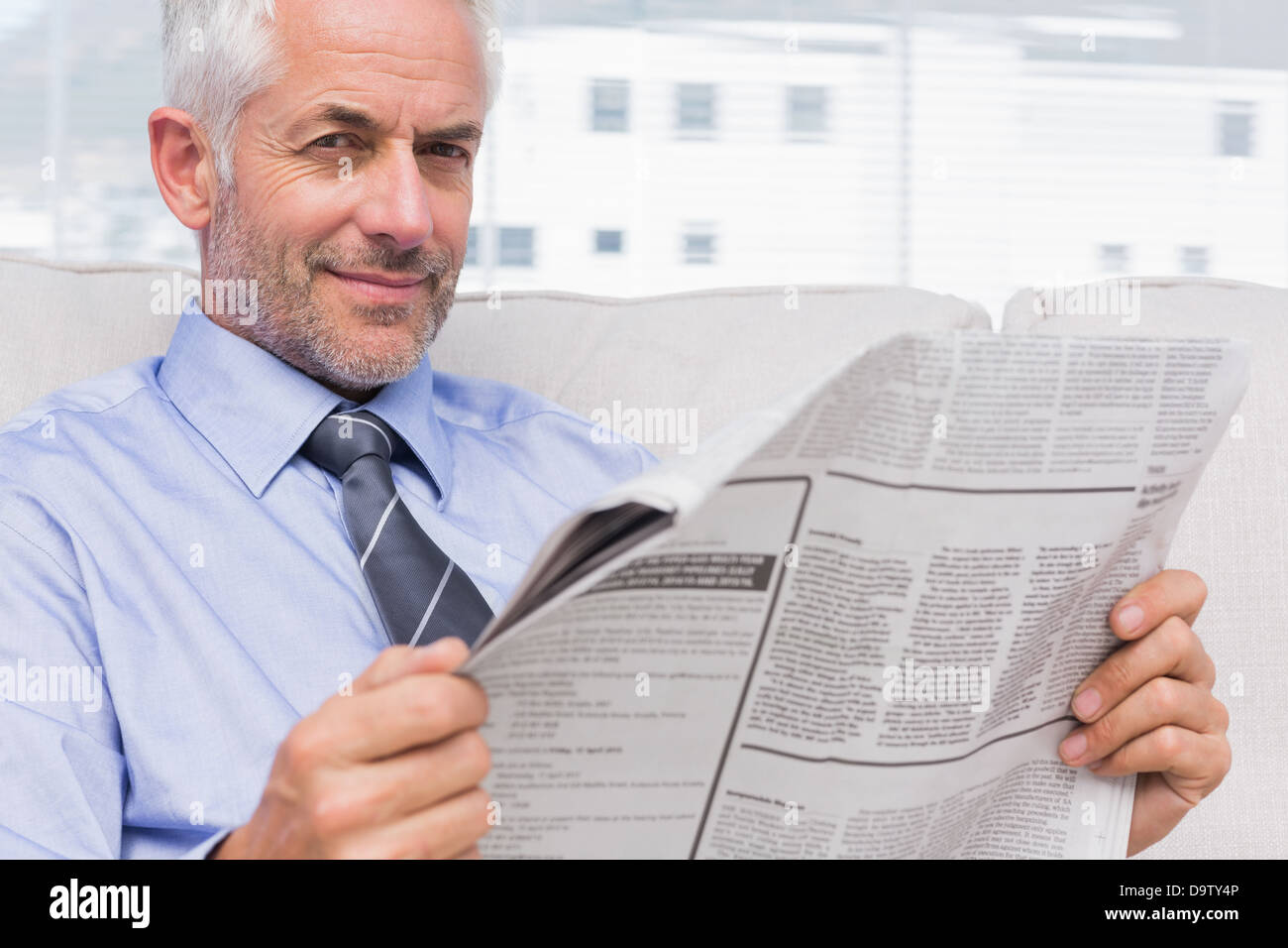 Smiling businessman holding a newspaper Stock Photo - Alamy