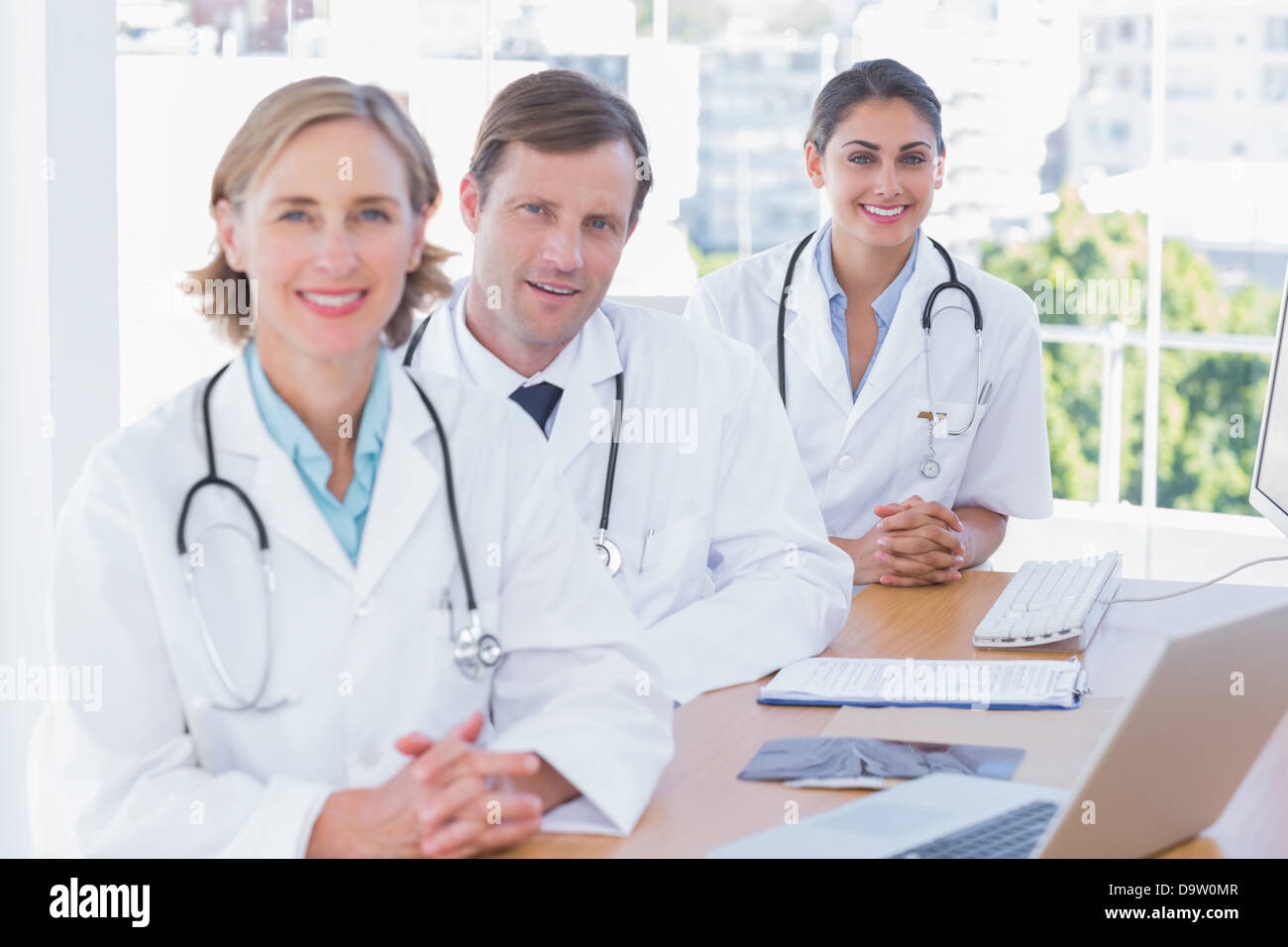 Smiling doctors posing at their desk Stock Photo - Alamy