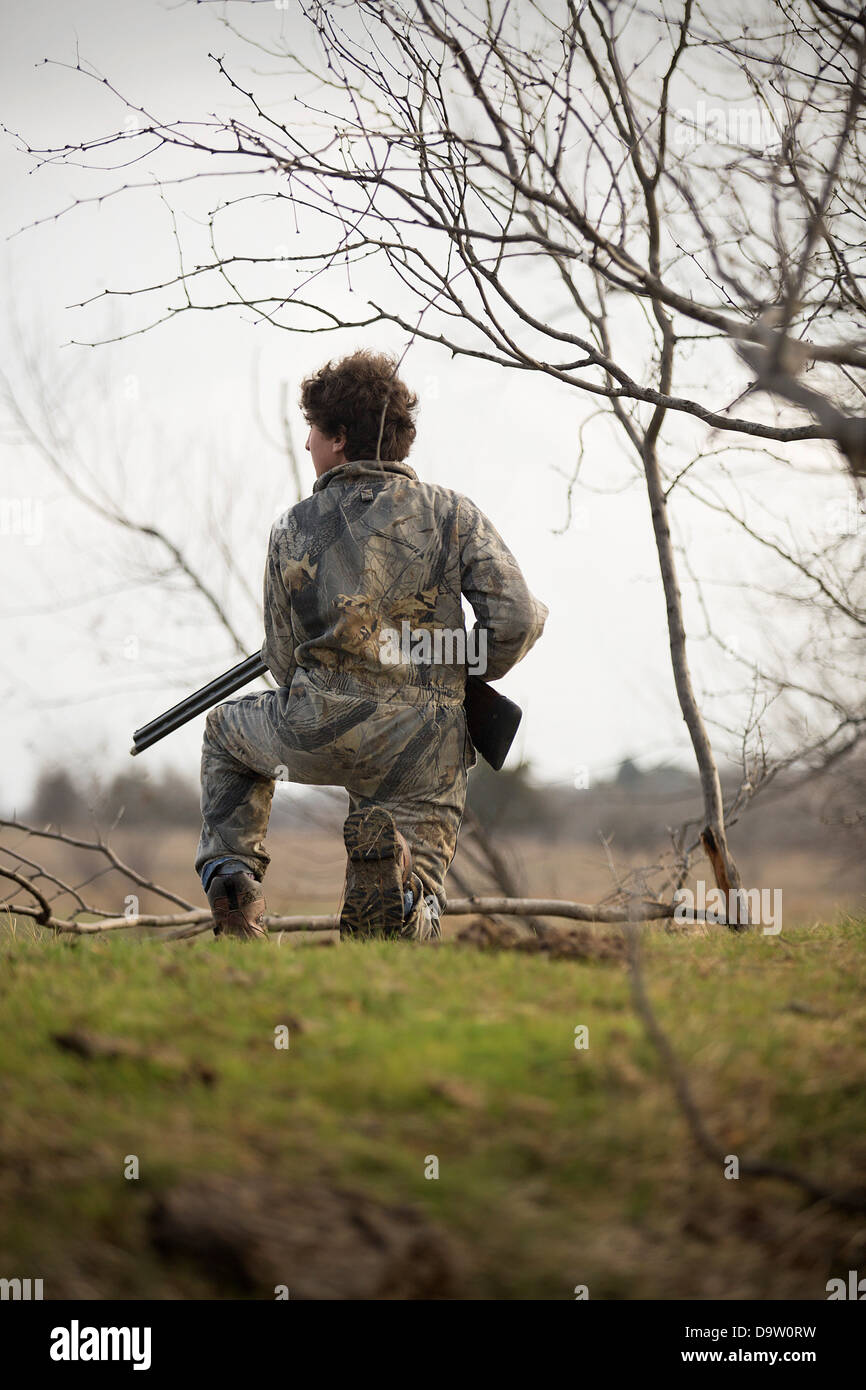 Duck hunter (12-13) kneeling on grass holding shotgun Stock Photo - Alamy