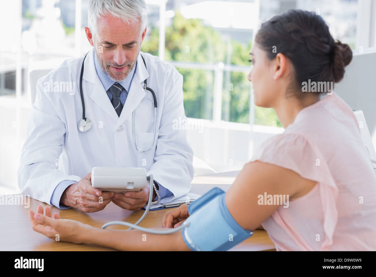 Doctor measuring blood pressure of a patient Stock Photo - Alamy