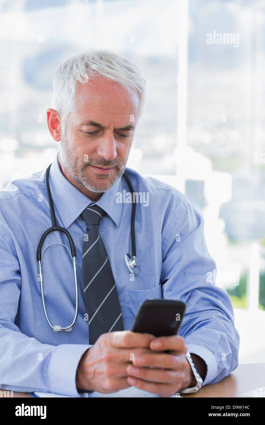 Doctor typing a text message on his smartphone Stock Photo - Alamy