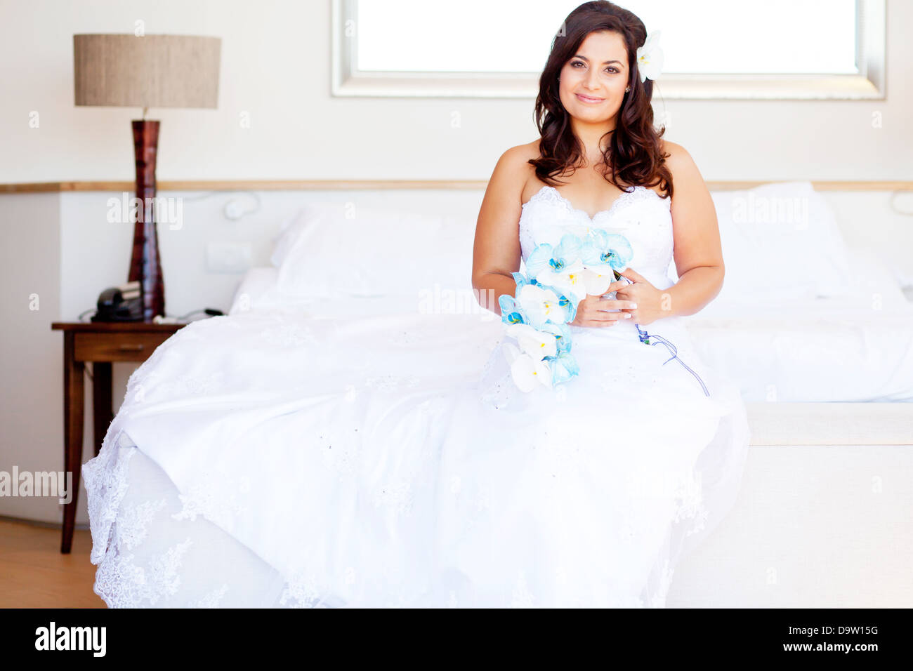 beautiful young bride sitting on bed with bouquet Stock Photo - Alamy