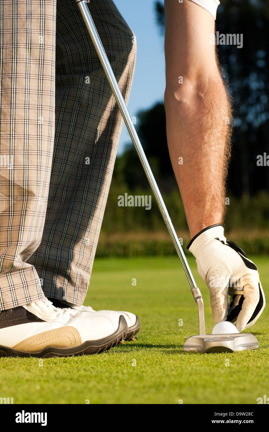 Man adjusting the golf ball in front of the hole ready to hit the cup ...