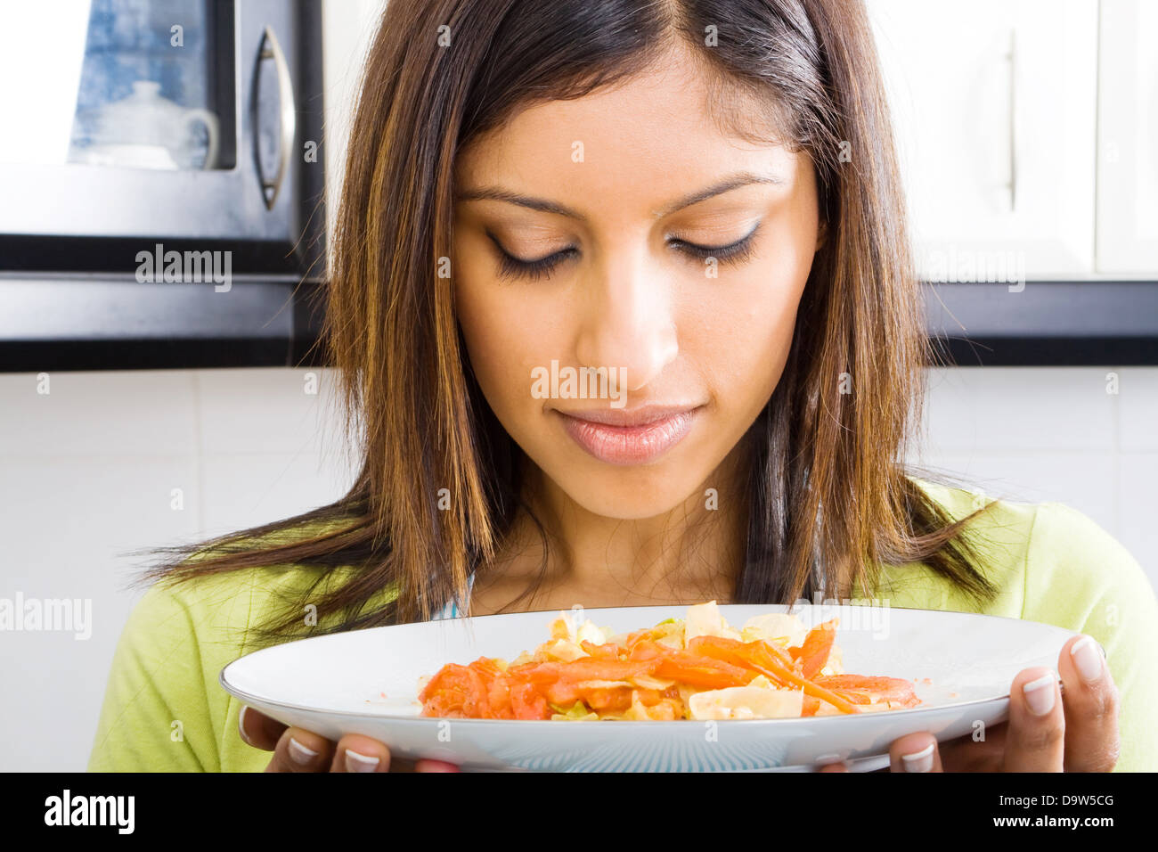 attractive young woman smelling warm food in kitchen Stock Photo - Alamy