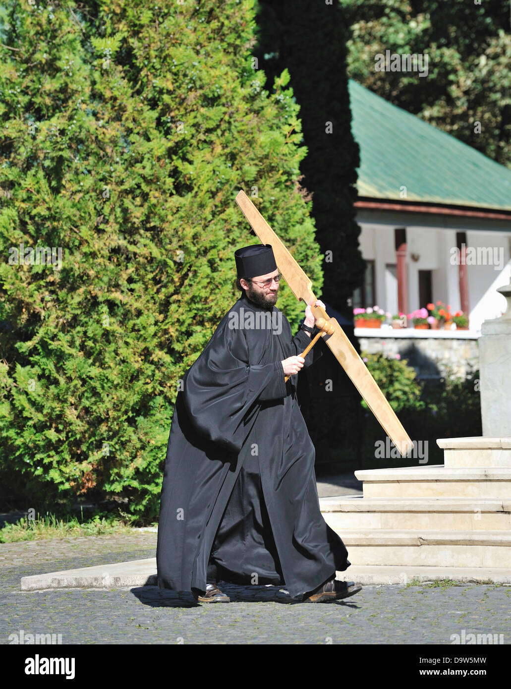 Monk calling to prayer with a wooden gong, Sinaia Monastery, Romania ...