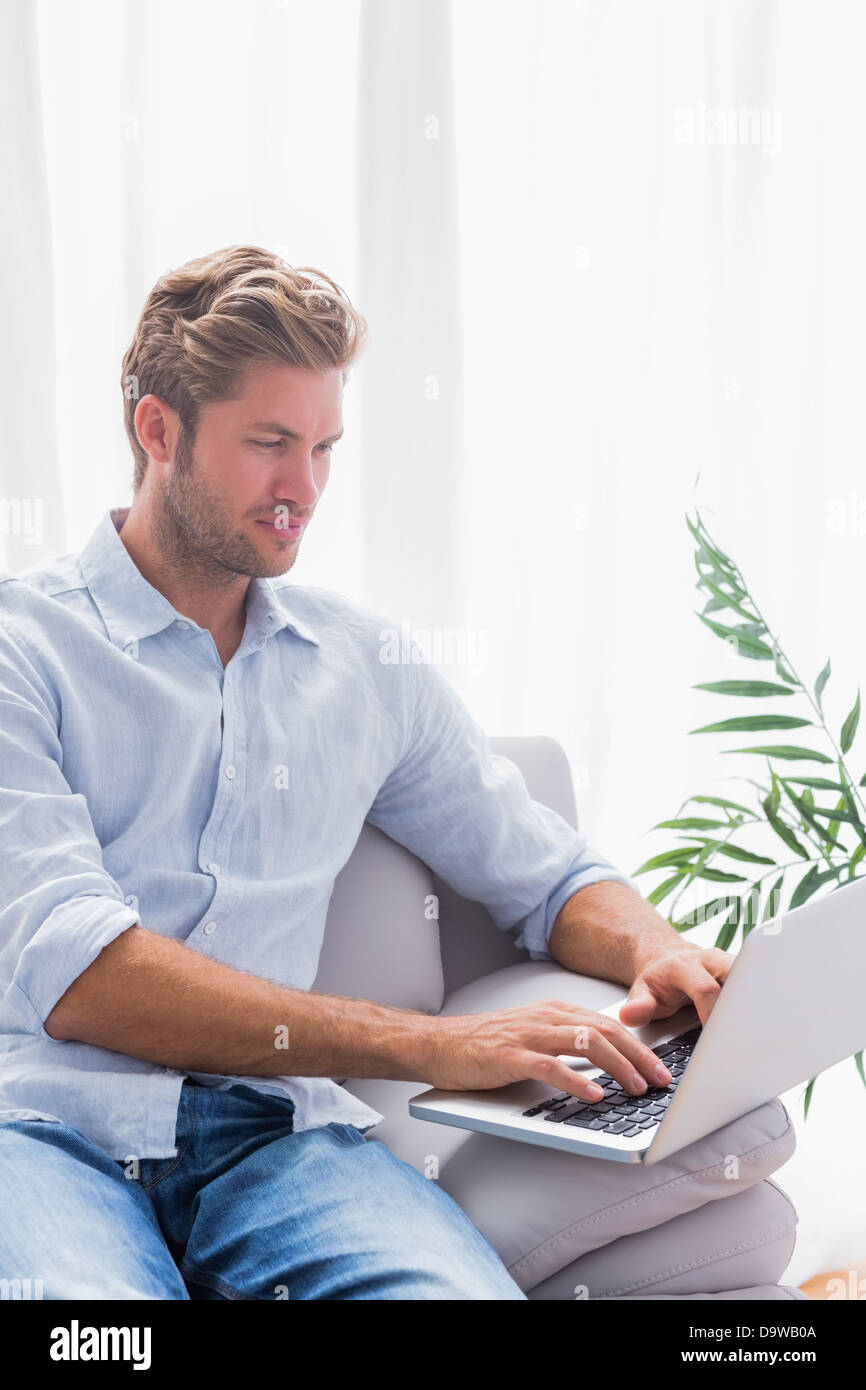 Serious man using his laptop on a couch Stock Photo - Alamy