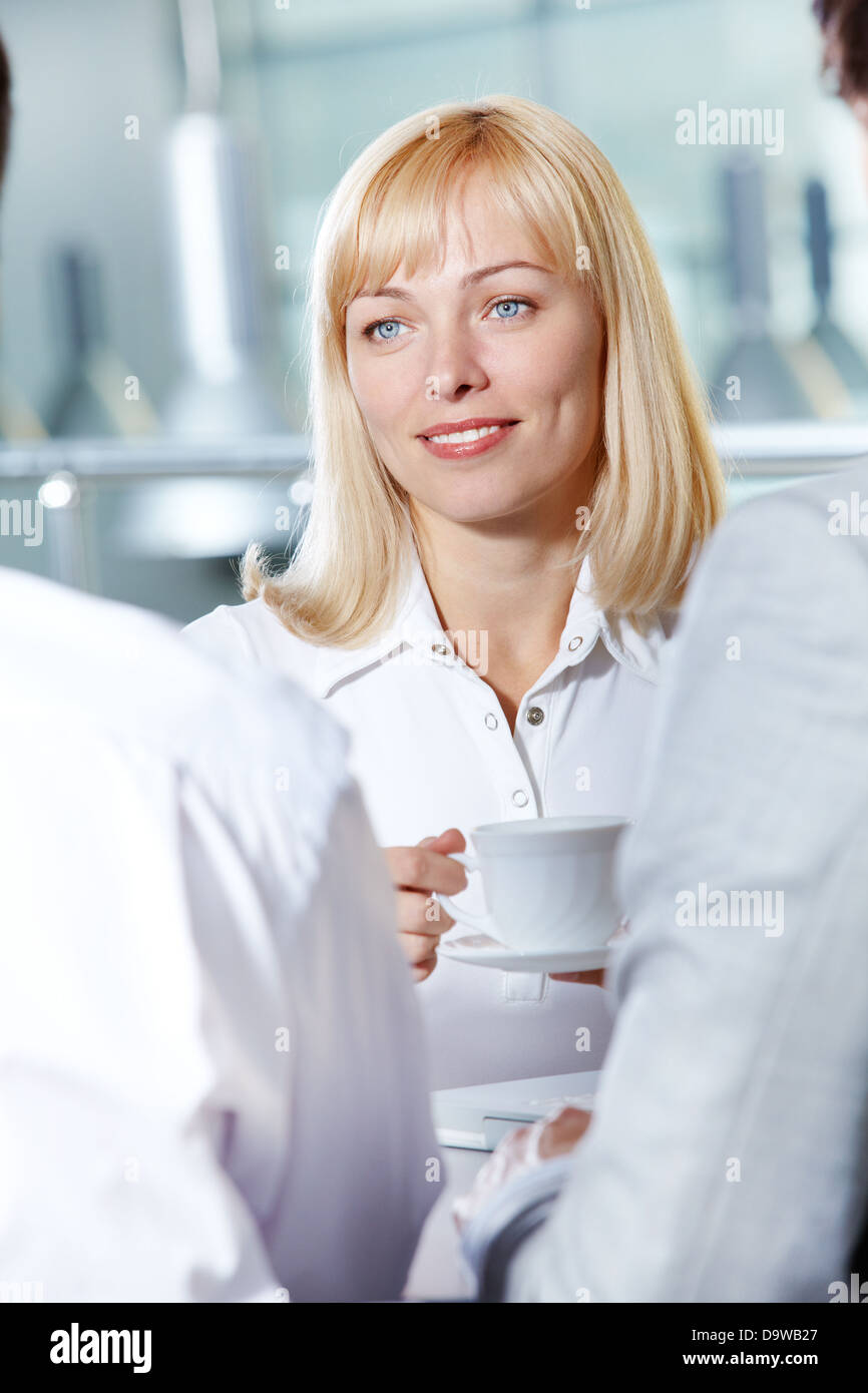 Portrait of pretty woman at workplace with coffee cup speaking to ...