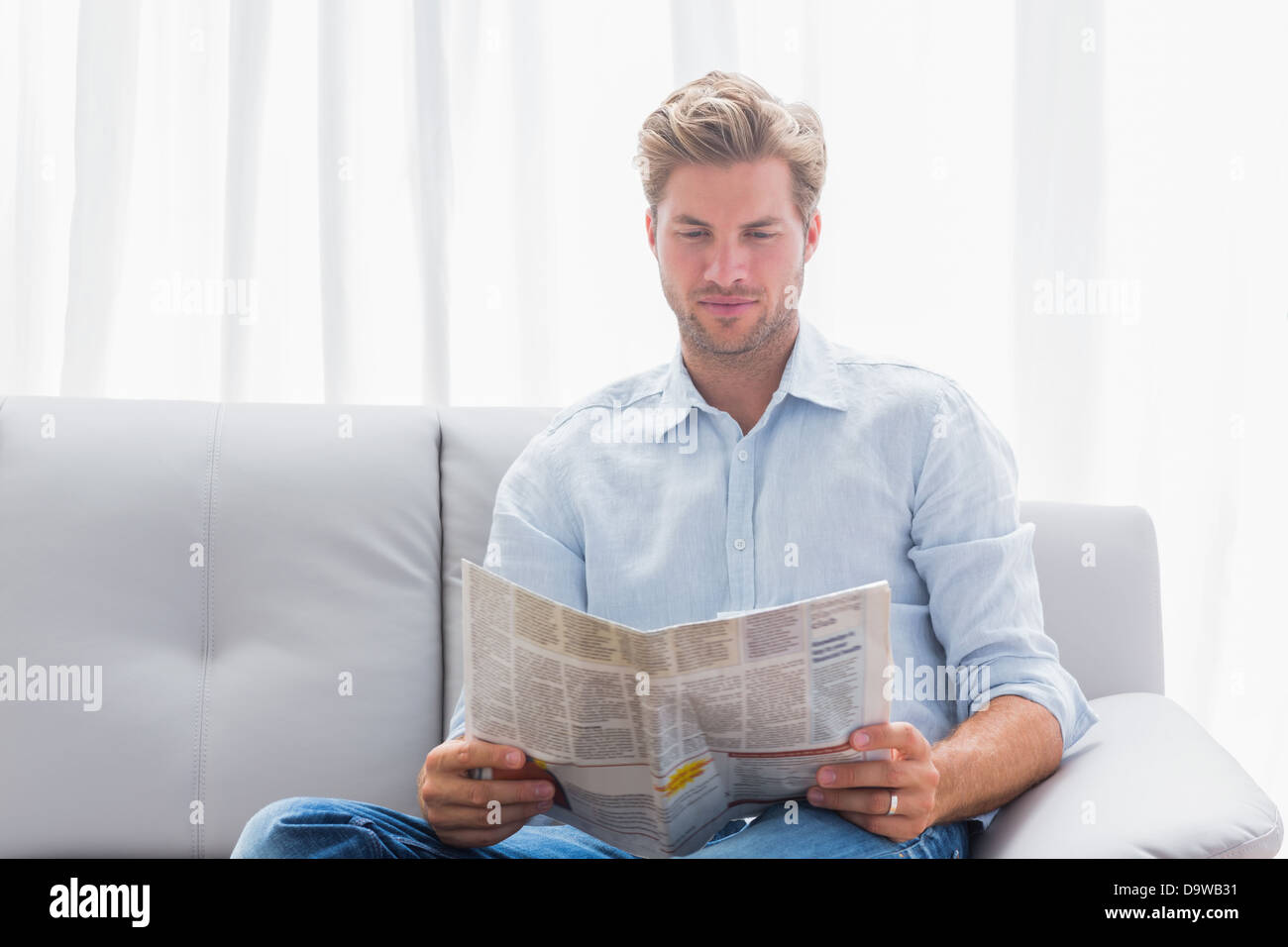 Man reading a newspaper on a couch Stock Photo - Alamy