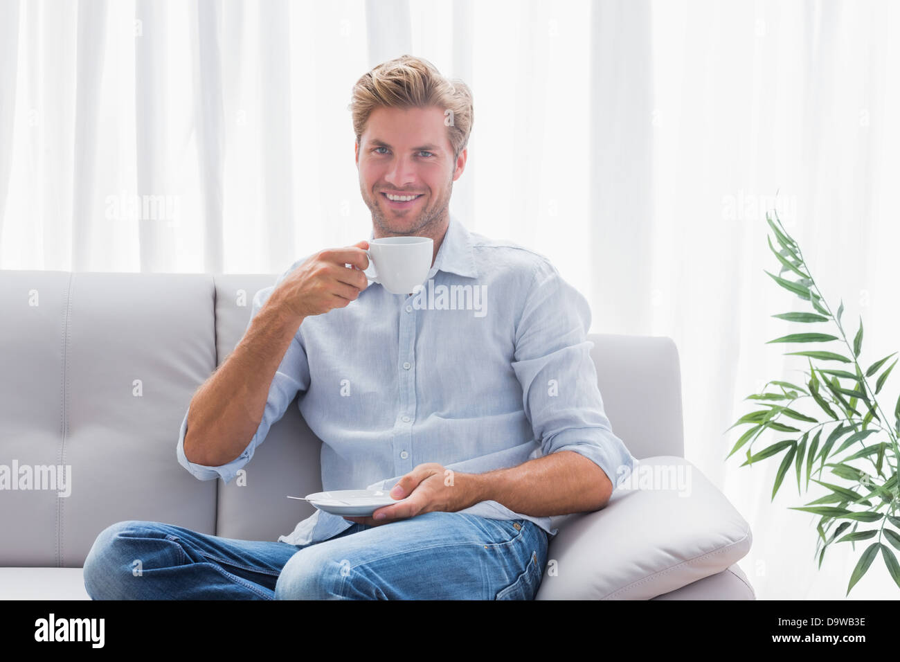 Man sitting on his couch drinking a coffee Stock Photo - Alamy