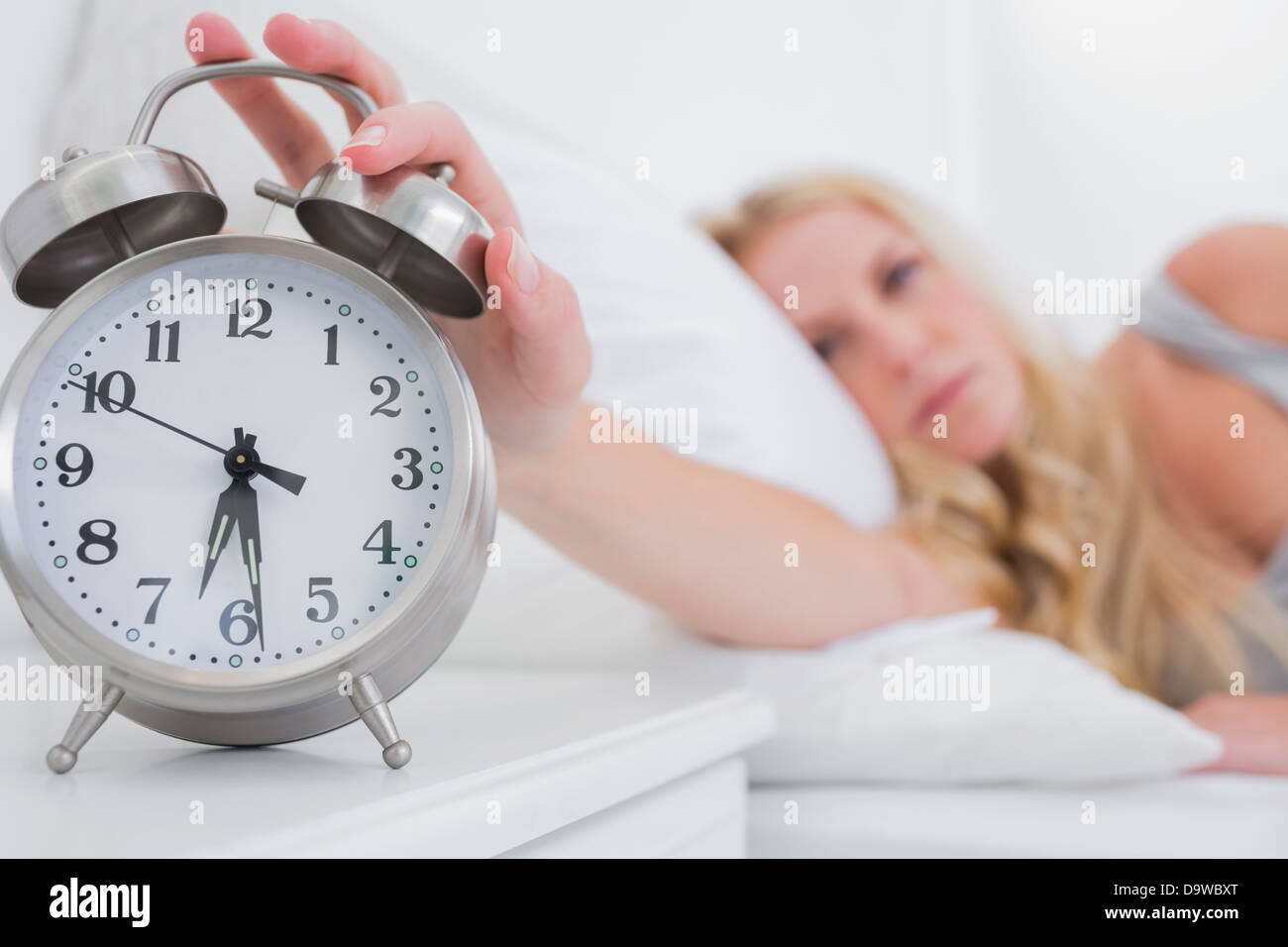 Tired woman turning off the alarm clock Stock Photo - Alamy