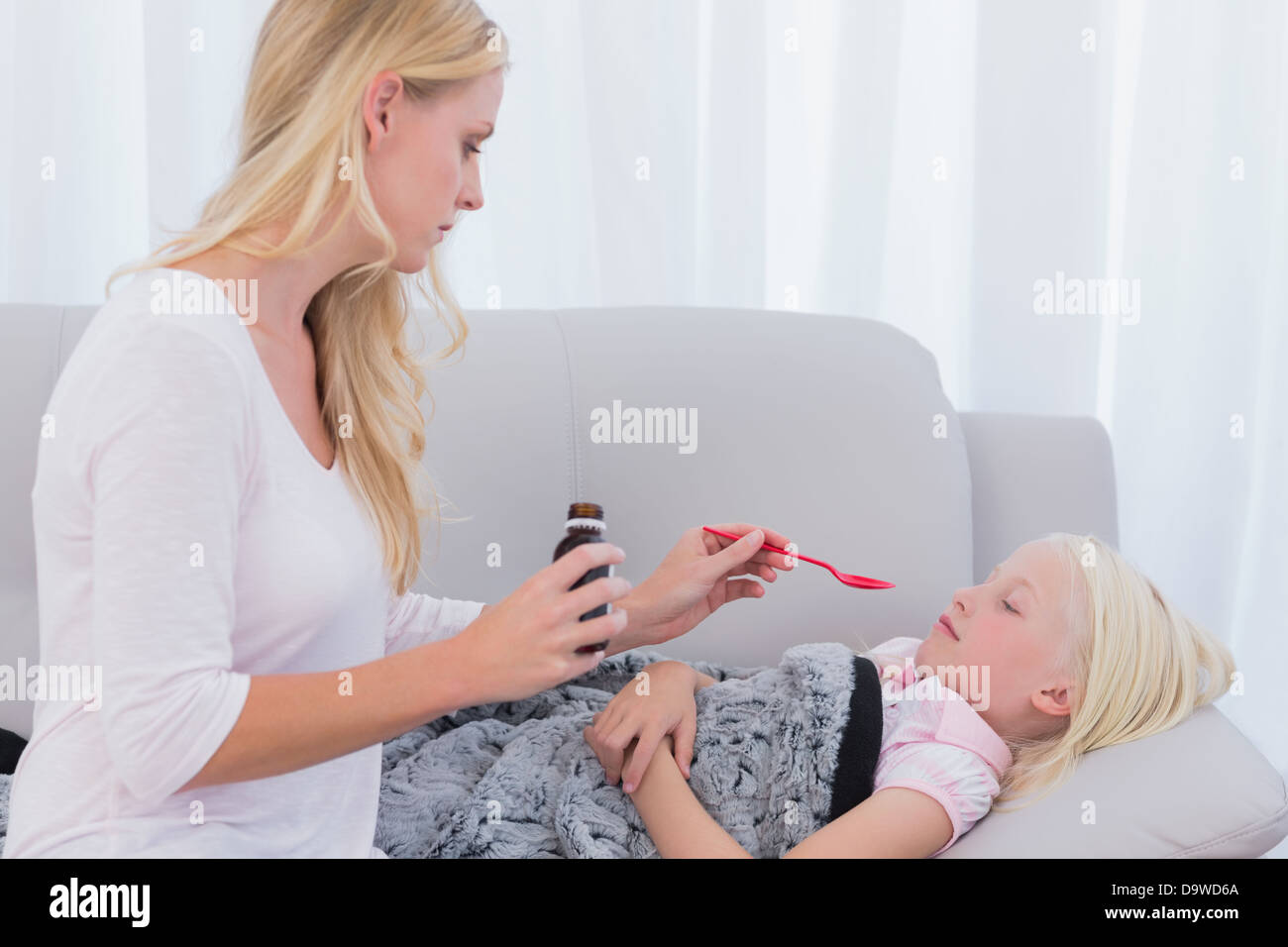 Concerned mother giving her daughter medicine Stock Photo - Alamy