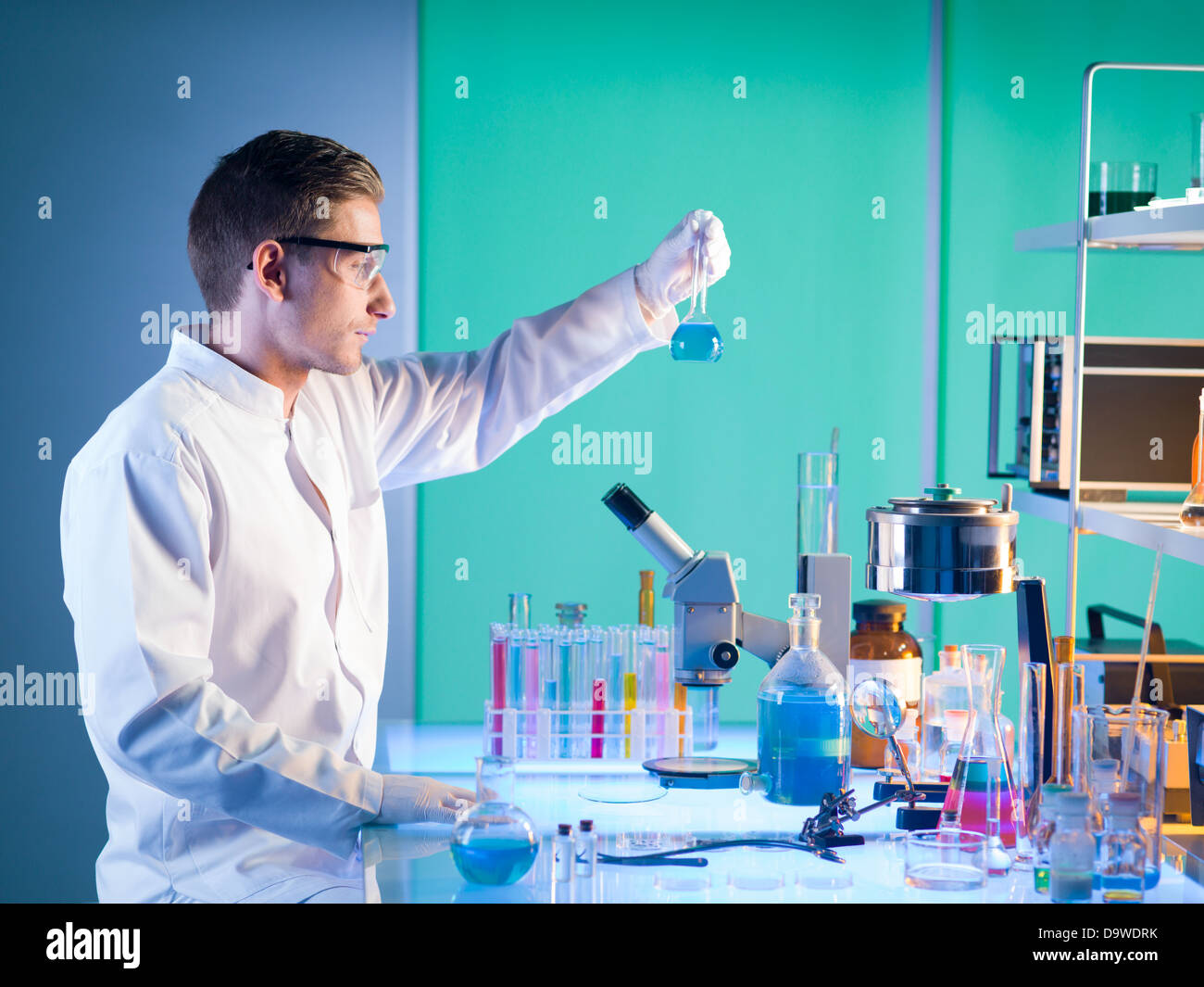 side view of pharmacist in a laboratory holding a chemistry bottle with ...