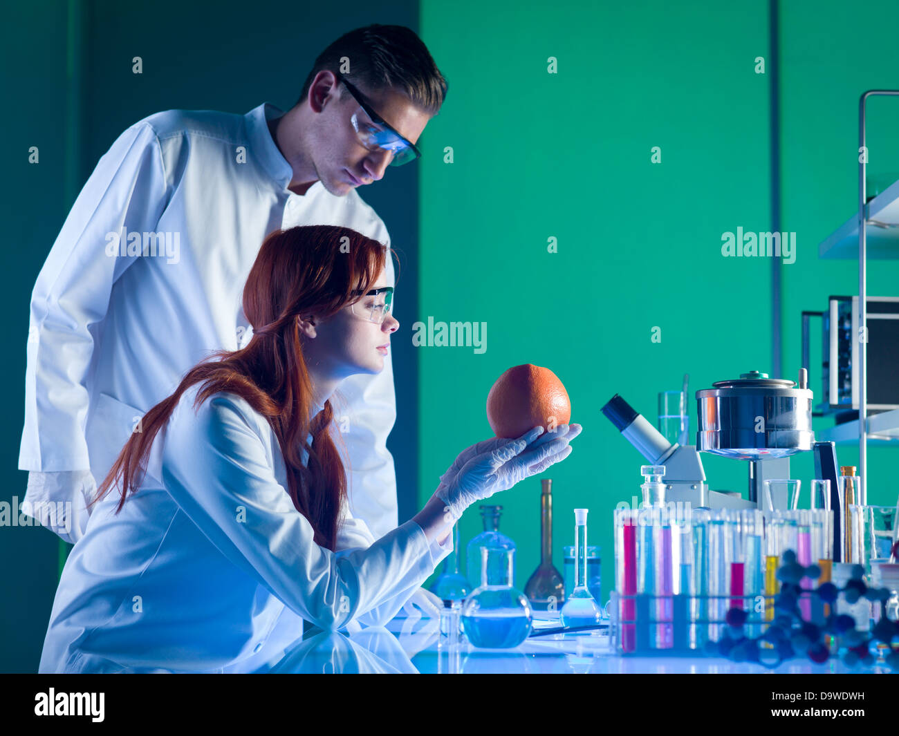 side view of scientists looking at a colorful grapefruit in a ...