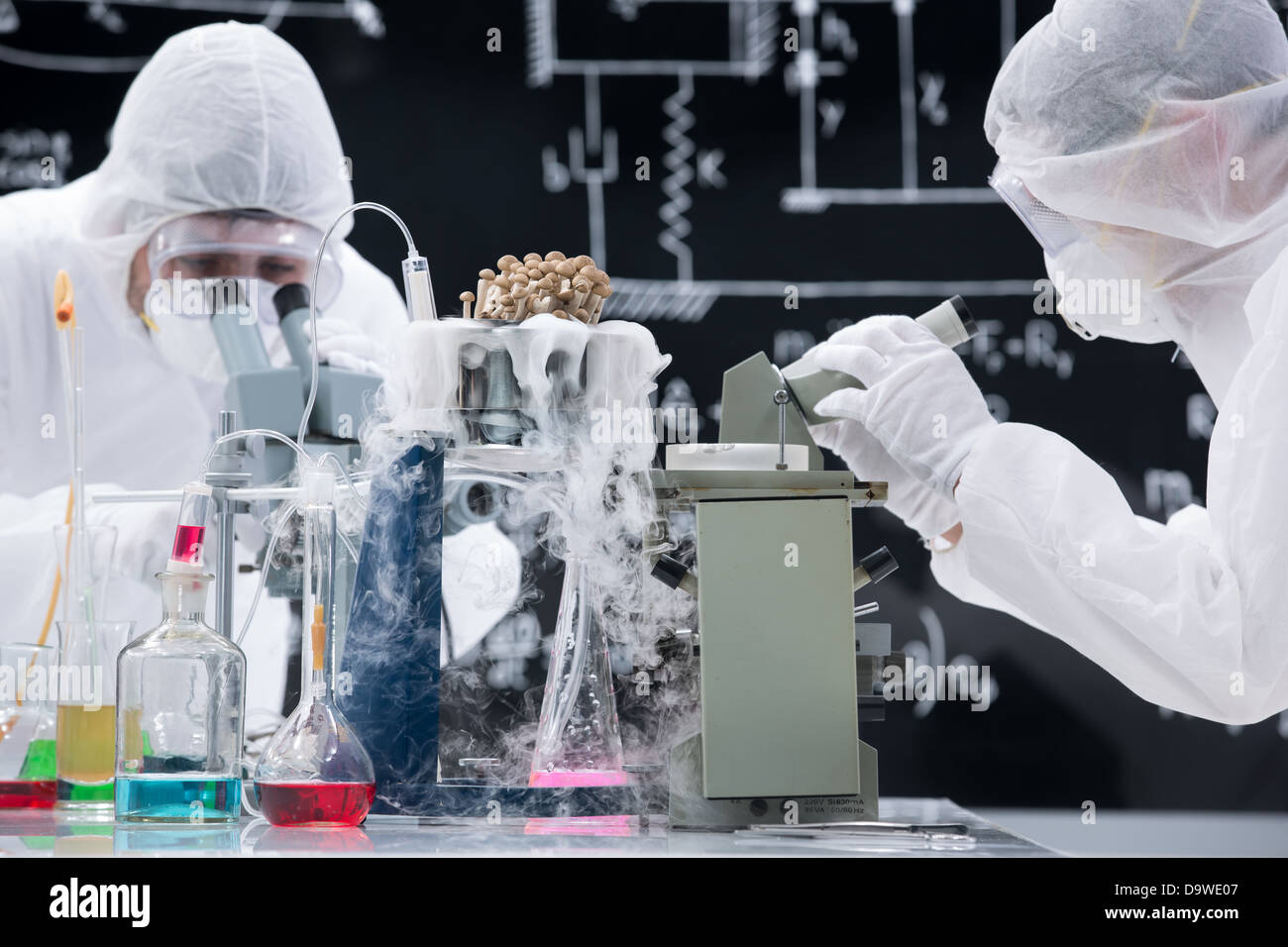 Laboratory scientists in sterile garb wearing masks and safety goggles ...