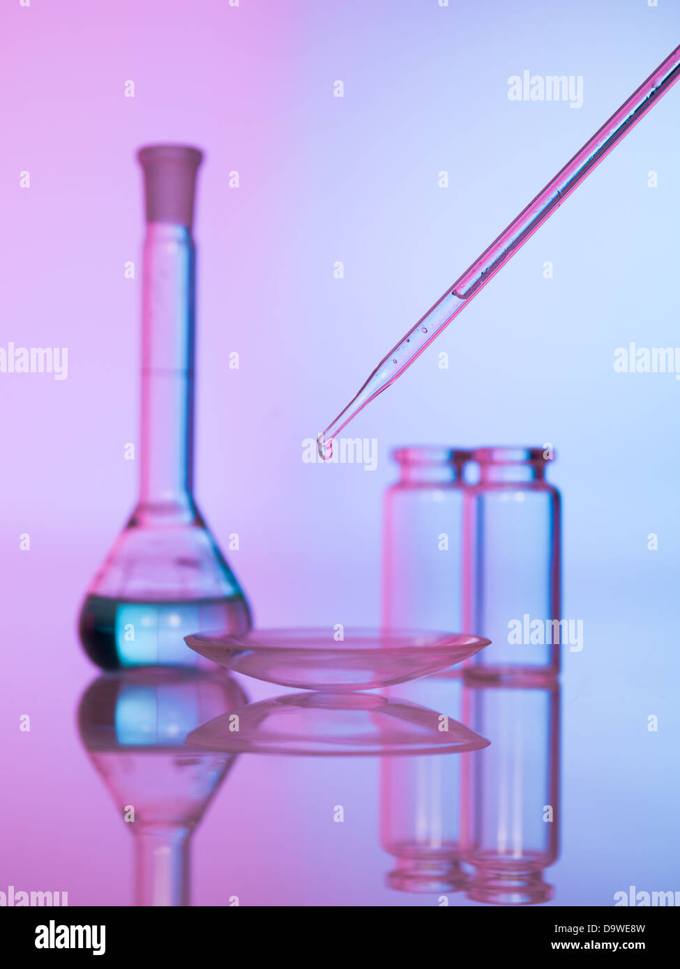 pipette dropping a transparent liquid in a dish with two empty glass ...