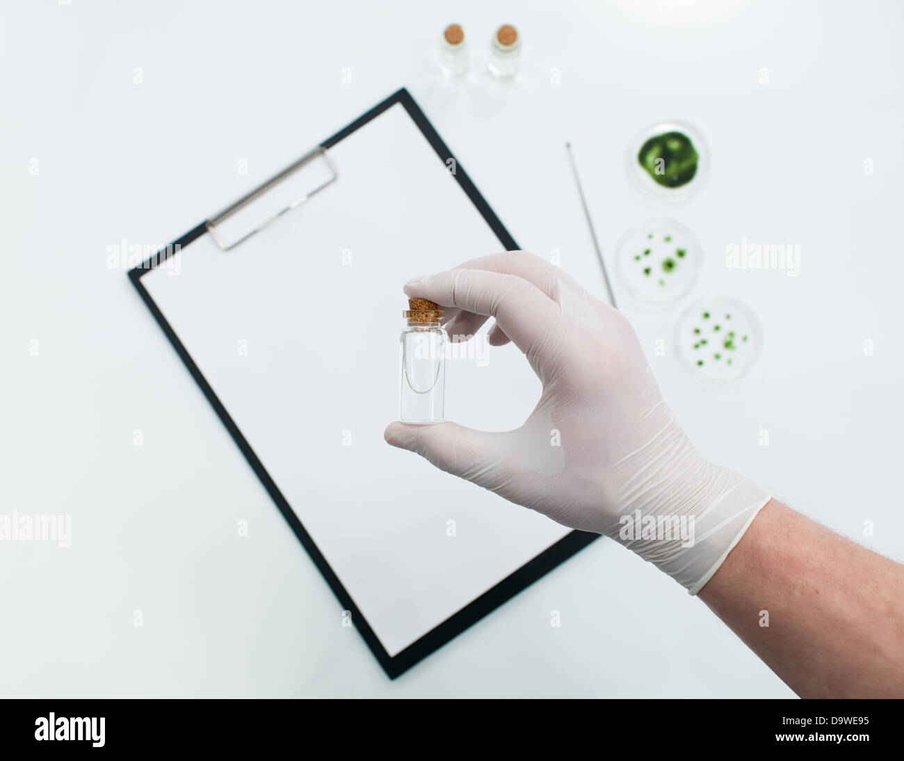 hand in white medical glove holding a small bottle with a transparent ...