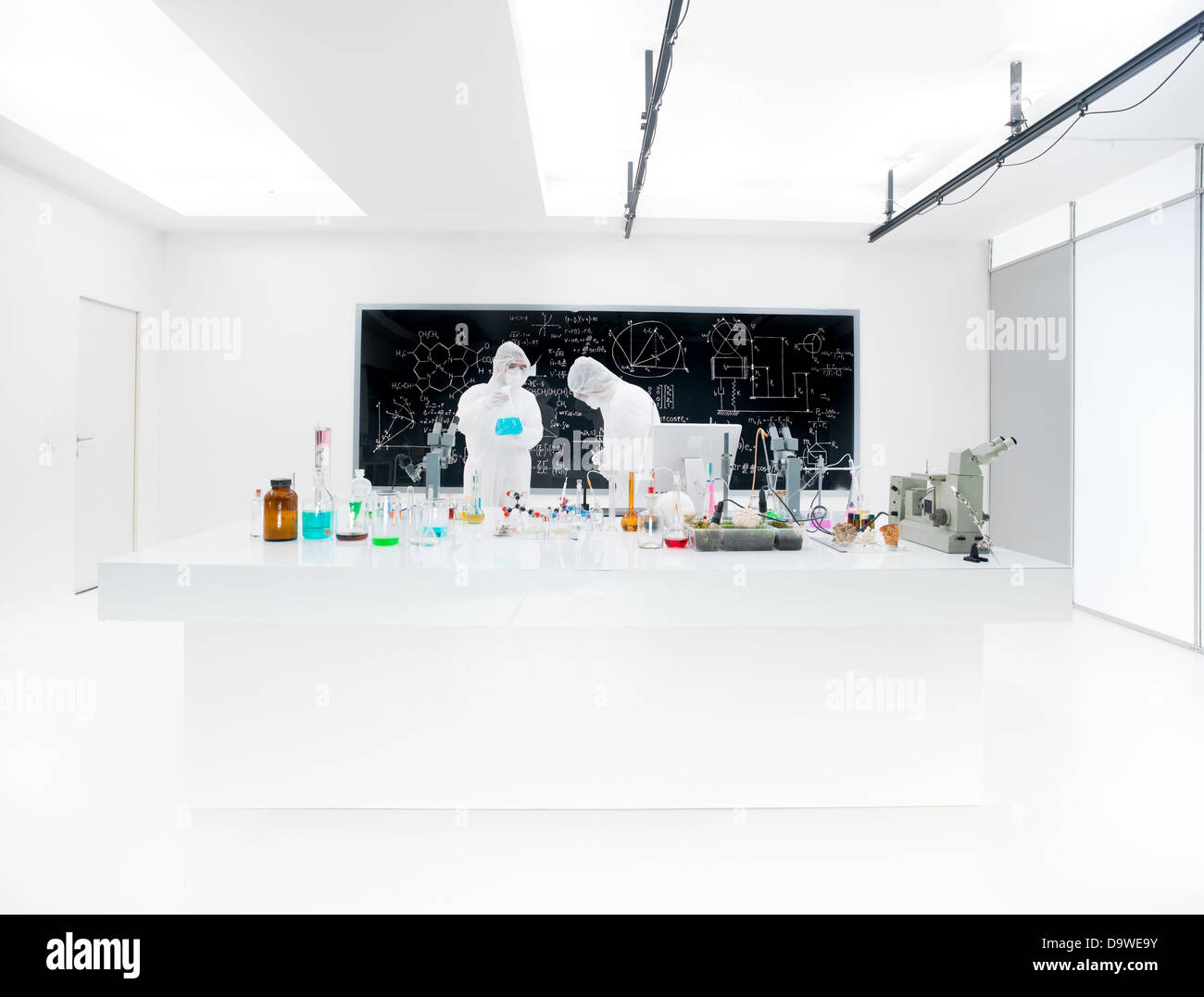 Two lab technicians working in a laboratory with vials wearing masks ...