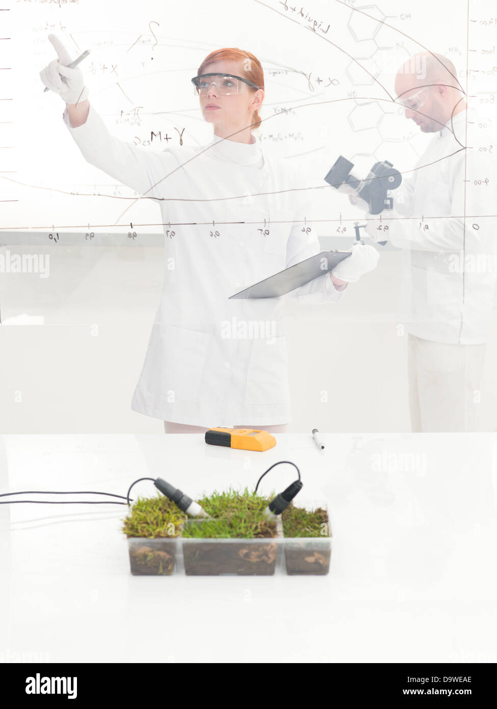 Female scientist monitoring a plant experiment standing checking a ...