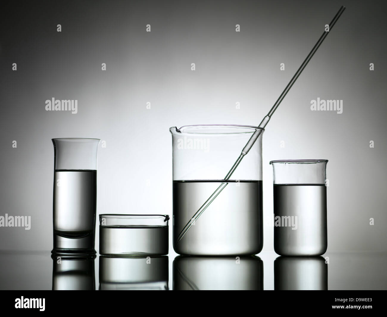 different sizes beakers filled with transparent liquid whith a dropper ...