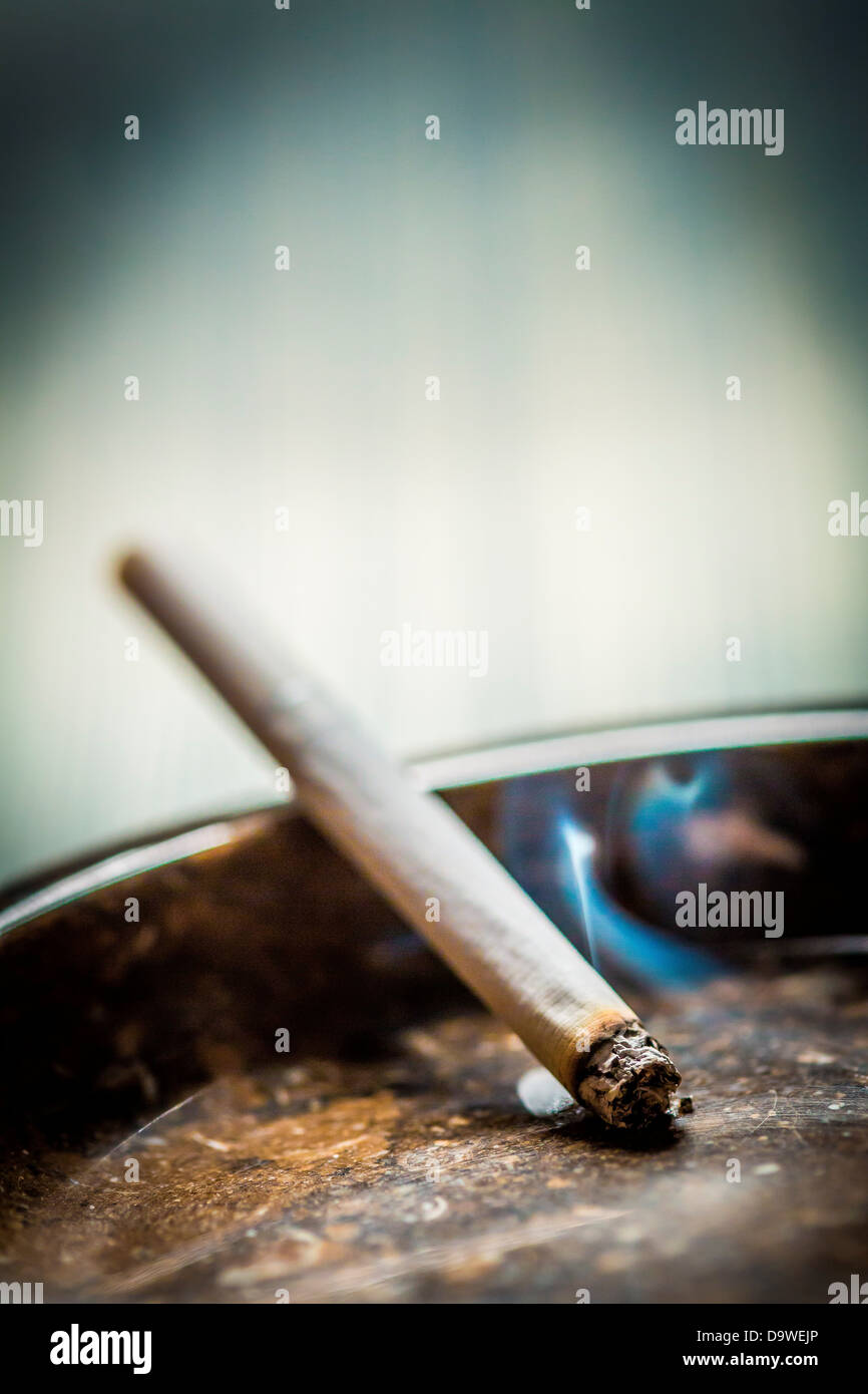 Lit cigarette in an ashtray Stock Photo - Alamy
