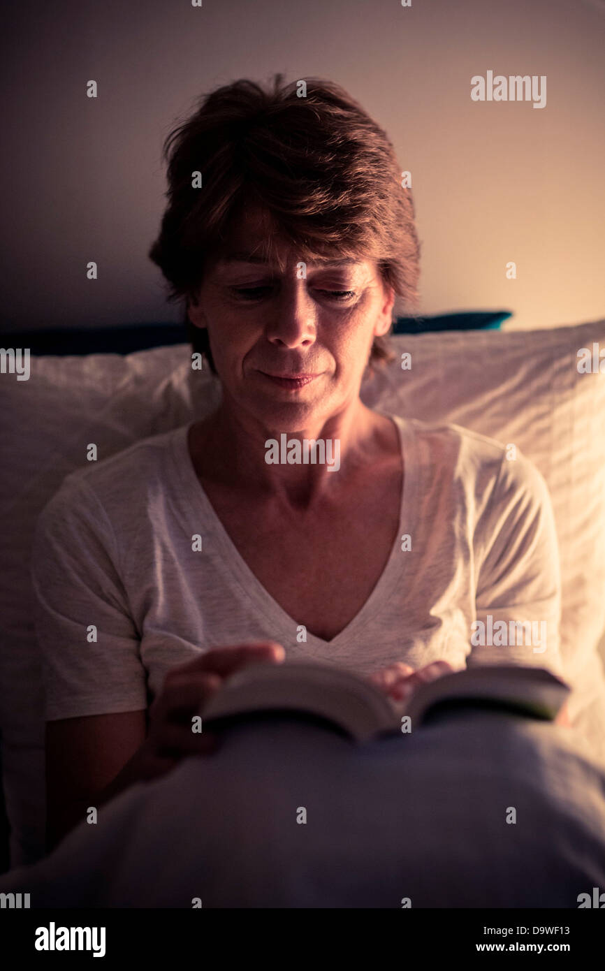 Restless woman reads a book in bed unable to sleep Stock Photo - Alamy