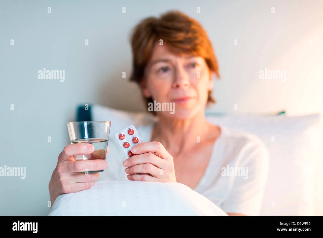 Restless woman taking tablets in bed unable to sleep Stock Photo - Alamy