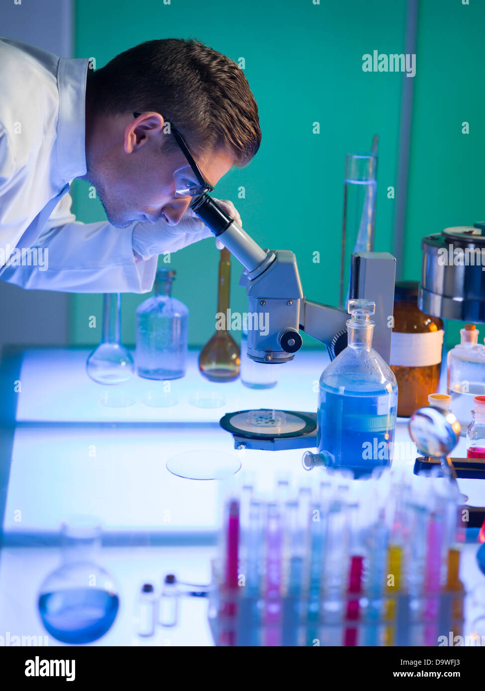 side view of male scientist analysing a sample through a microscope in ...