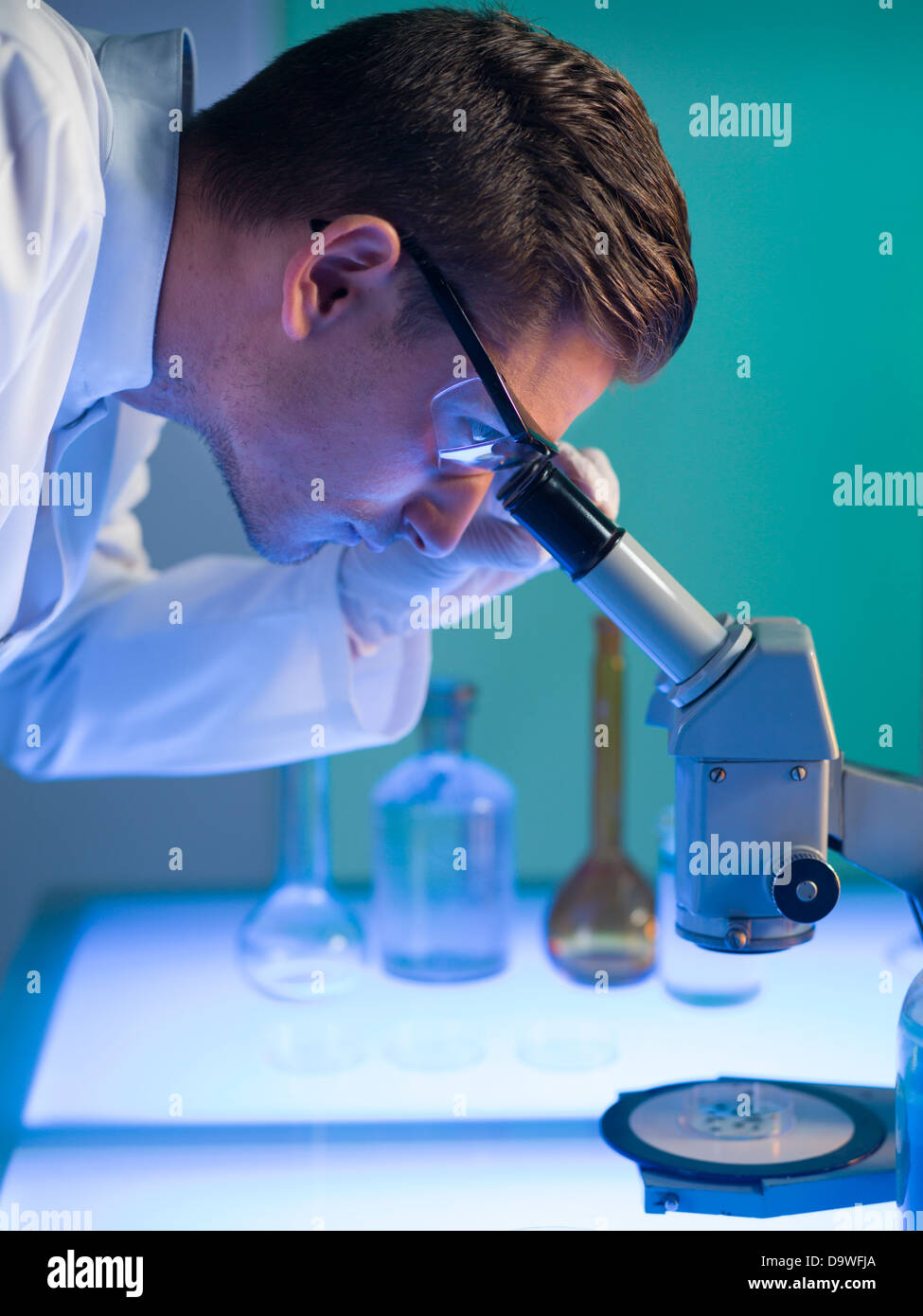 close-up of male scientist studying a sample through a microscope, in a ...