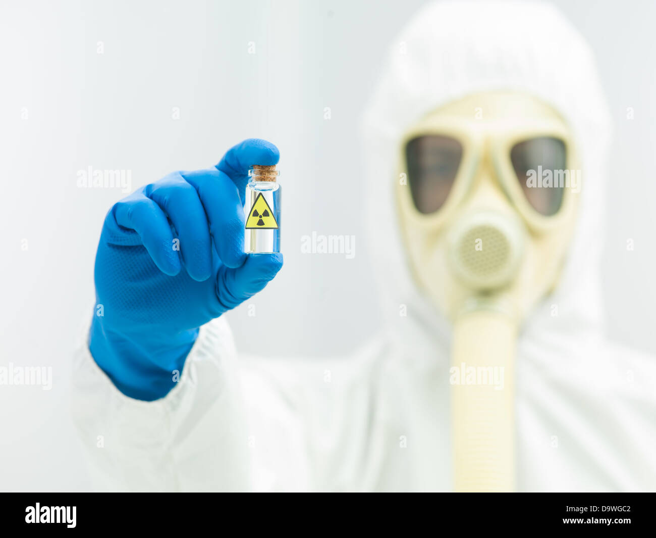 person in bio hazard suit and gas mask holding a radioactive isotope ...