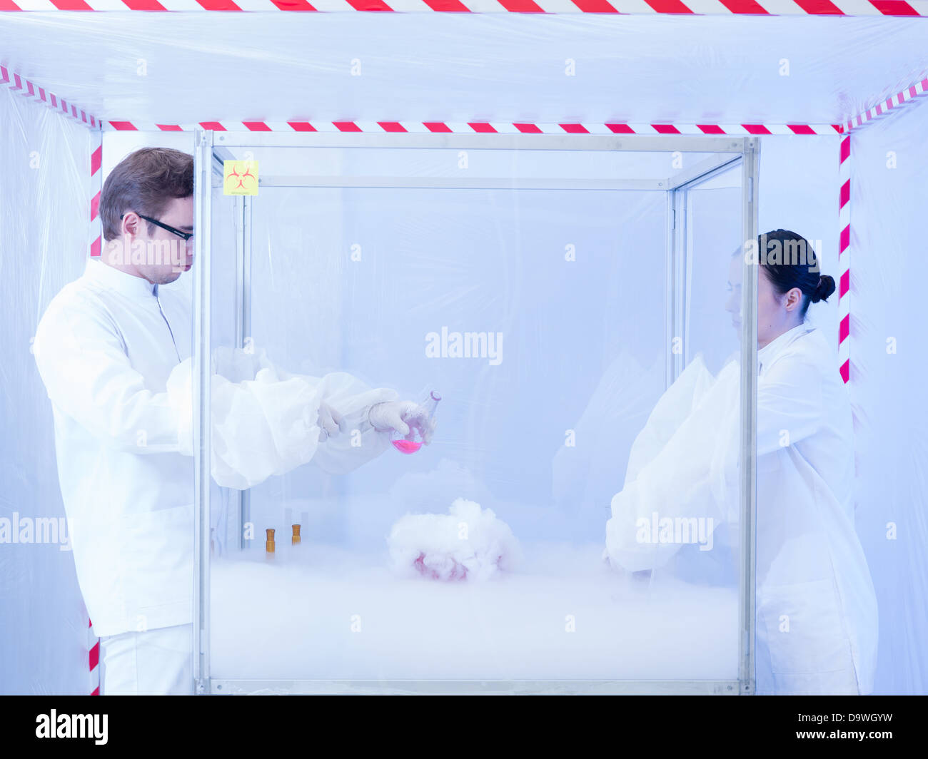 two scientists in a containment tent, a man and a woman, experimenting ...