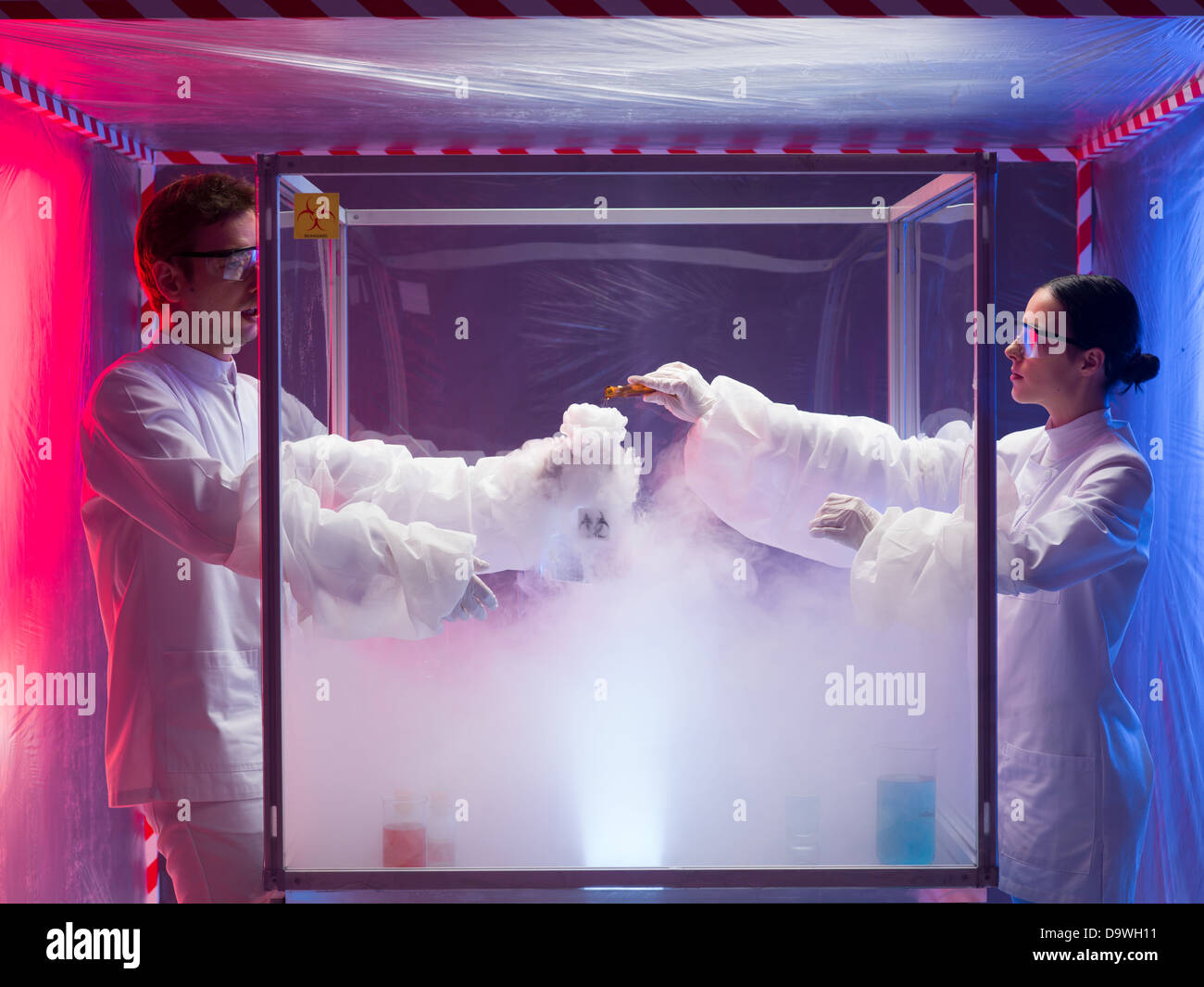 two scientists, a man and a woman, mixing chemicals in a sterile ...