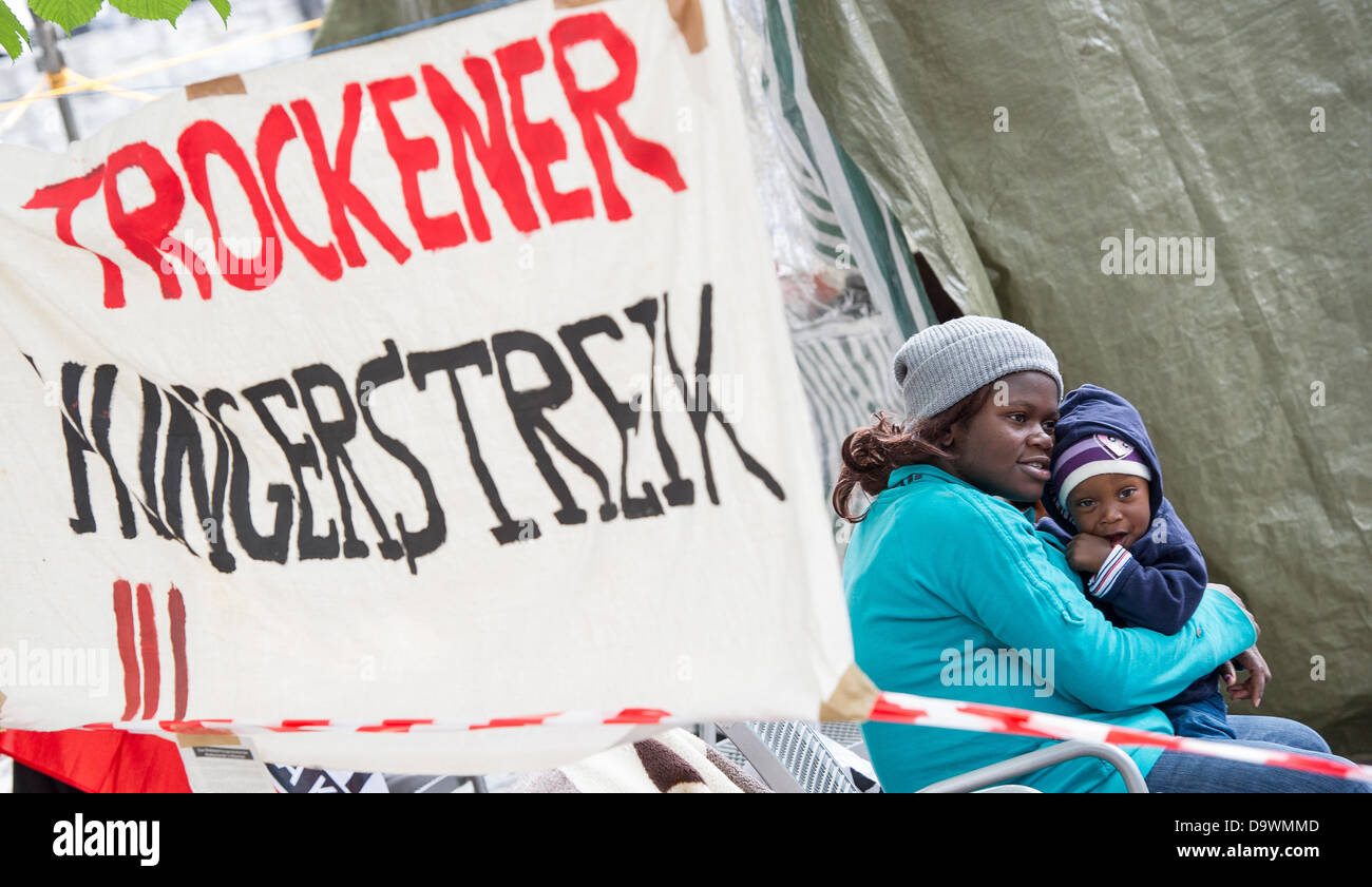 A mother and her child sit next to a banner saying 'Dry Hunger Strike ...