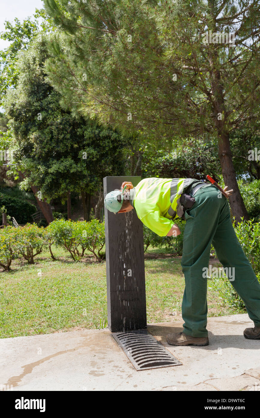 Park ranger gardener drinking from water drinking fountain in Parc de ...