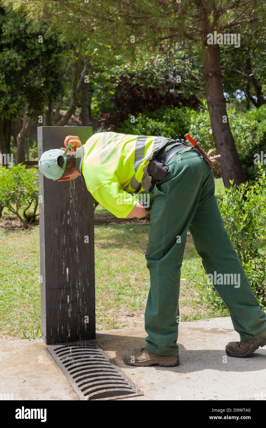Park ranger gardener drinking from water drinking fountain in Parc de ...