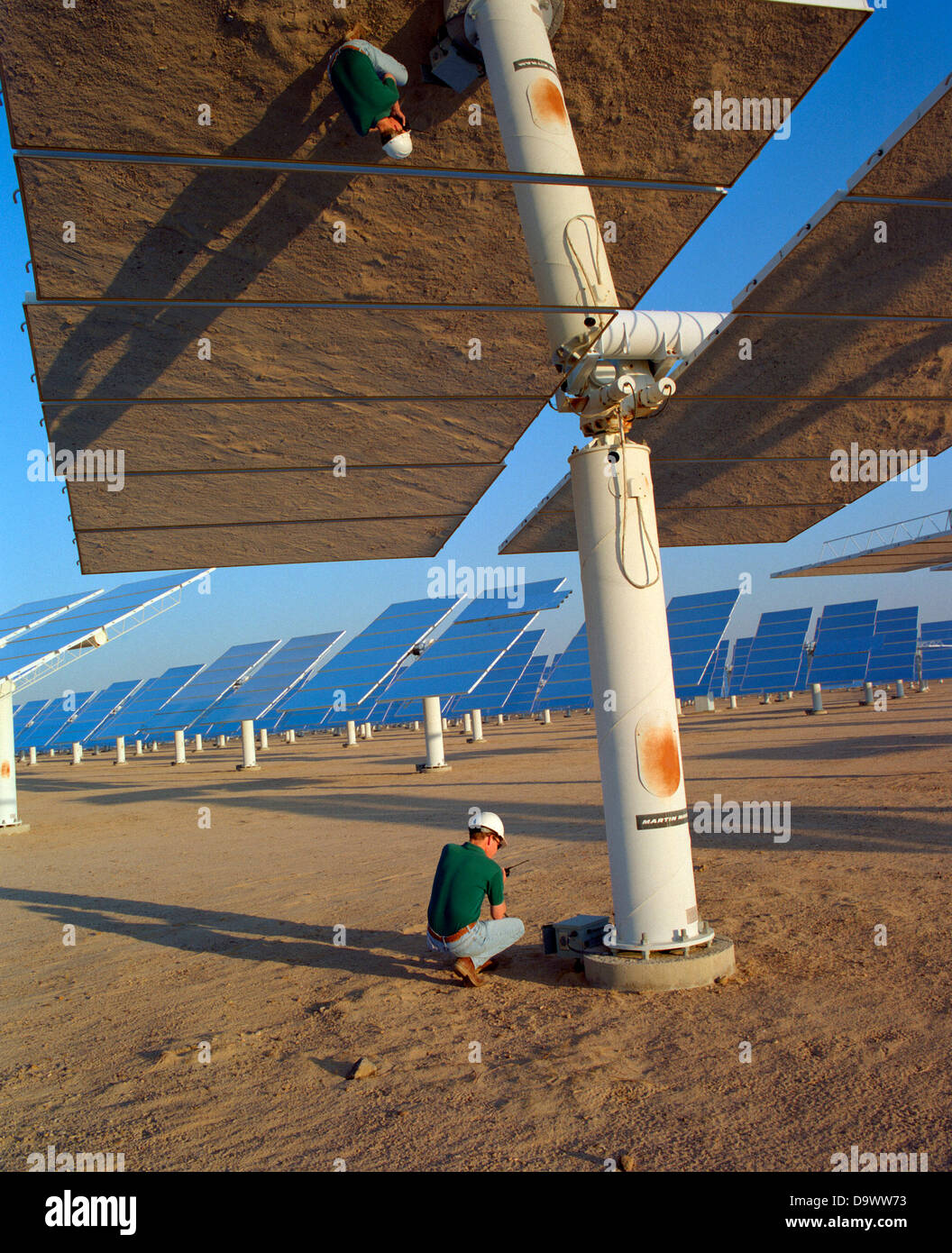 A technician checks the alignment of sun tracking mirrors at the Solar ...