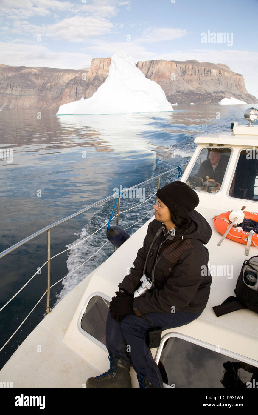 A tour boat passenger enjoys the view of icebergs and mineral rich ...