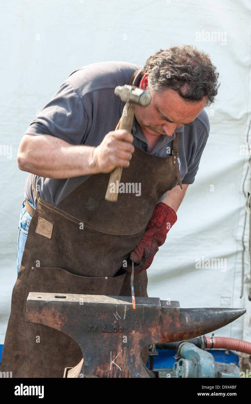 A blacksmith hammering red hot metal on an anvil during a competition ...