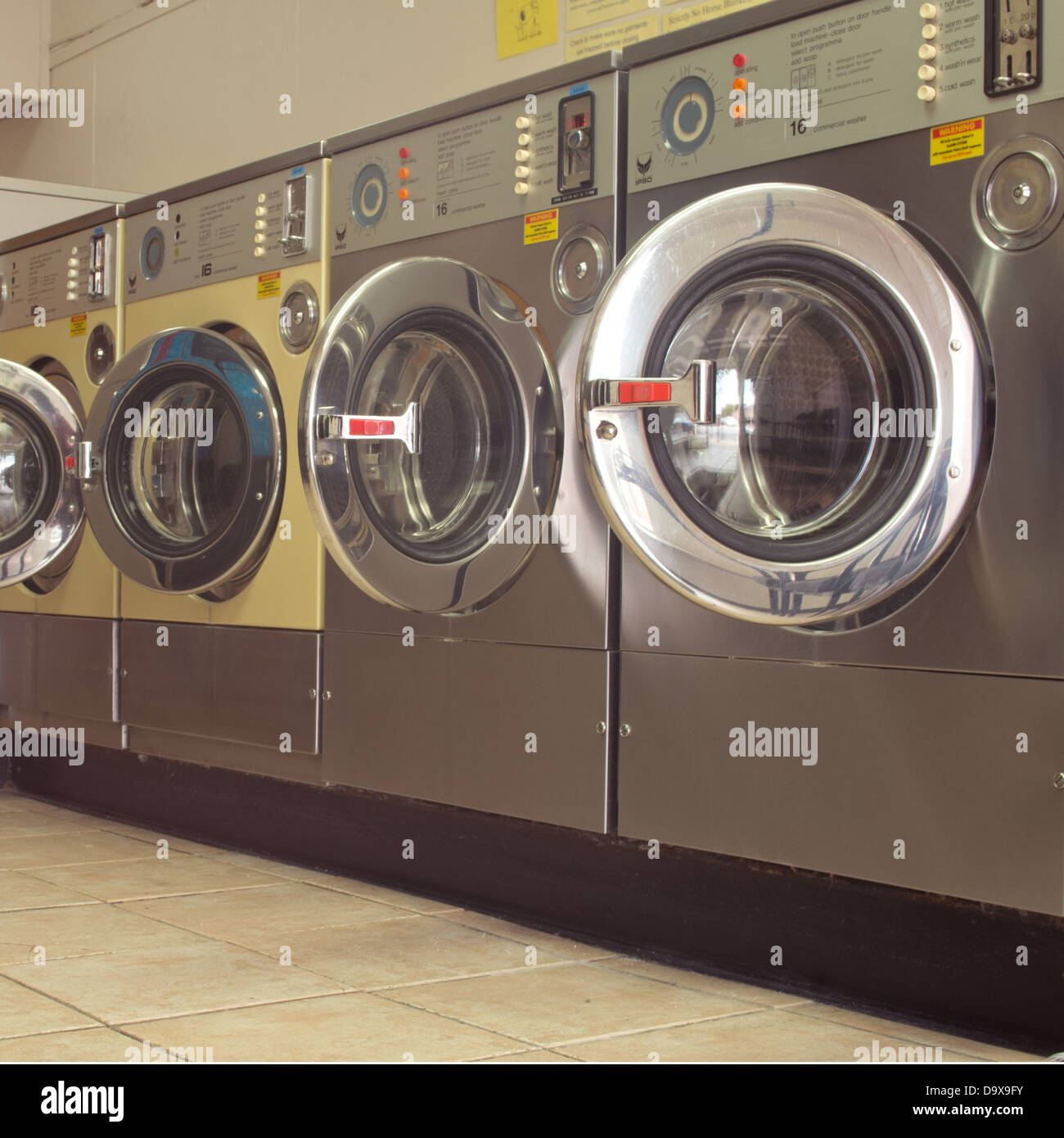 Row of coin operated stainless steel washing machines in Laundrette ...