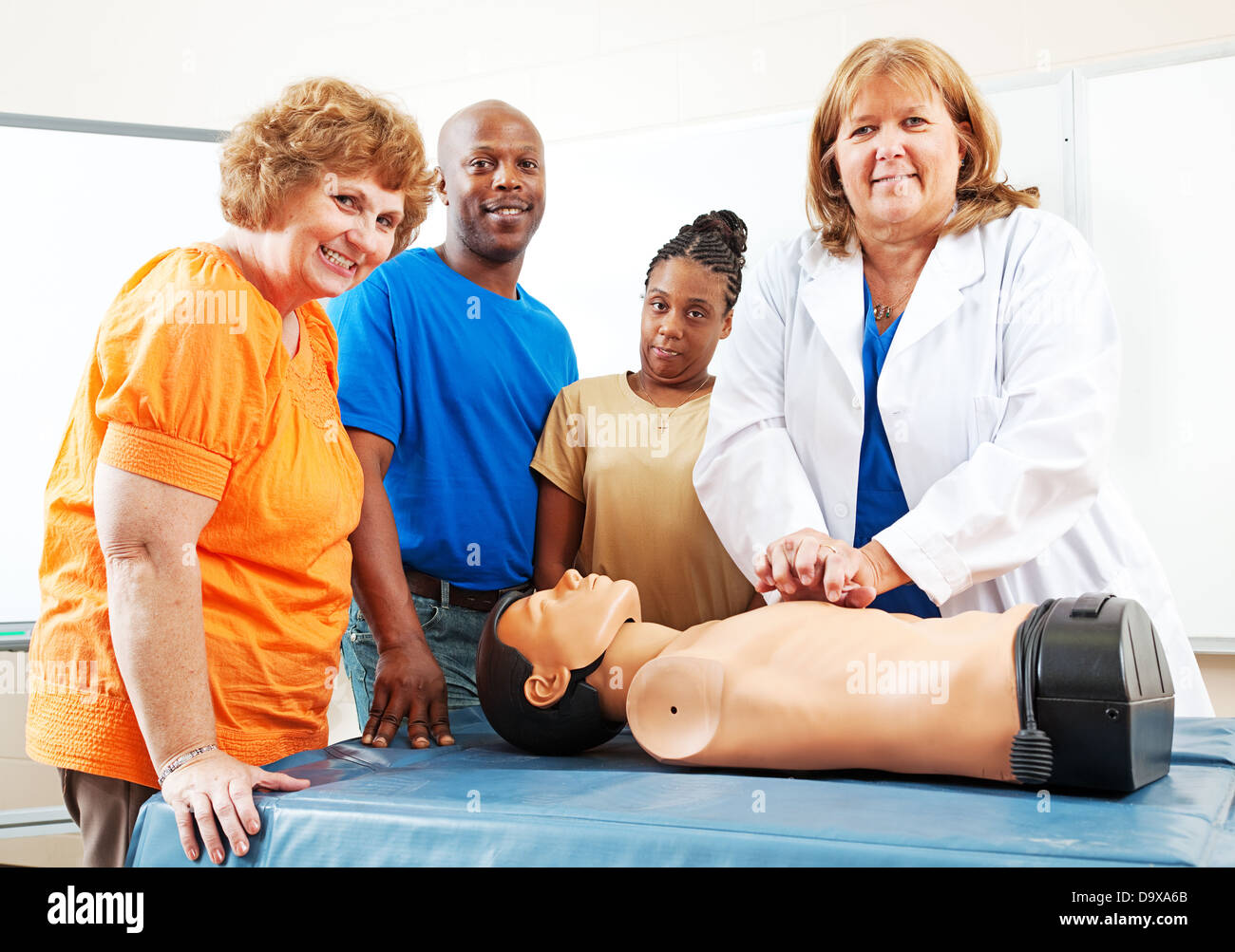 Adult students watching a nurse or doctor perform CPR on a mannequin ...