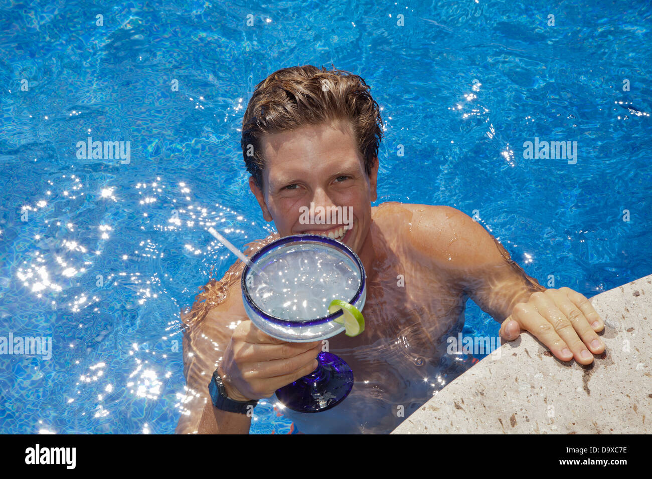 Young man in pool holding cocktail Stock Photo - Alamy