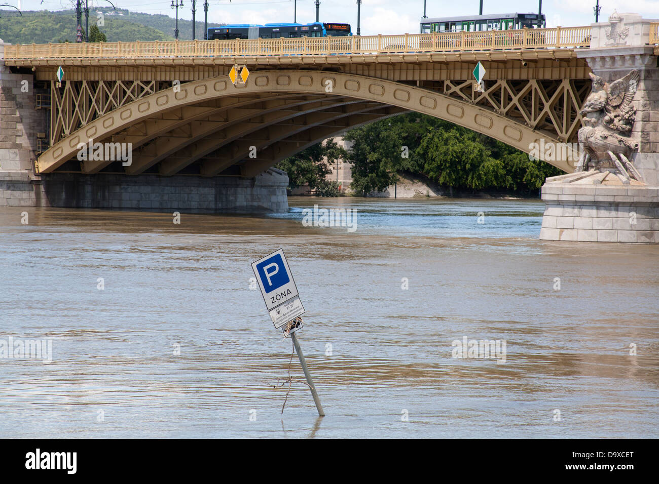 A road sign surrounded by water in a street flooded by the near ...
