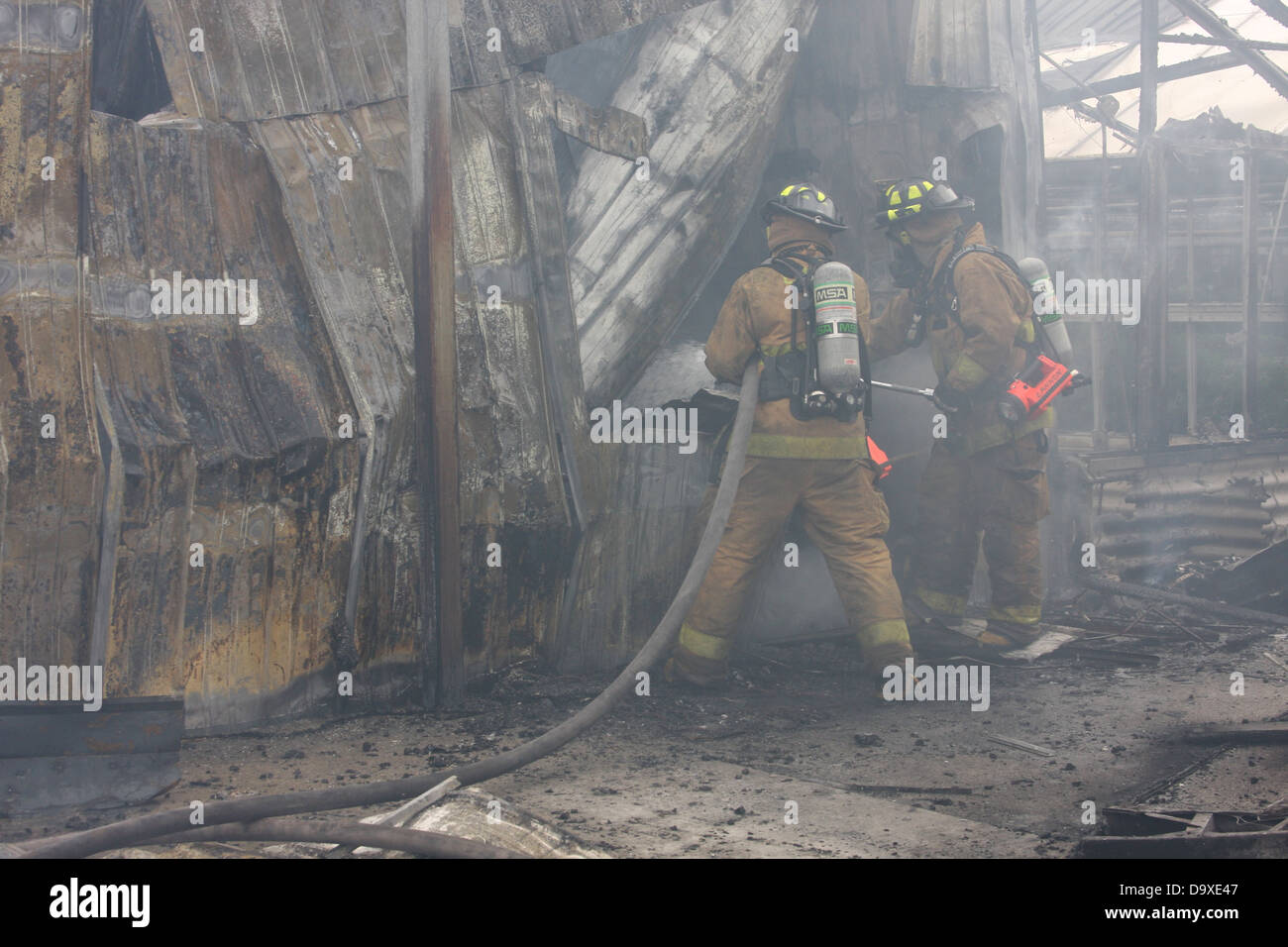 Two firefighters putting out a fire with a water hose Stock Photo - Alamy