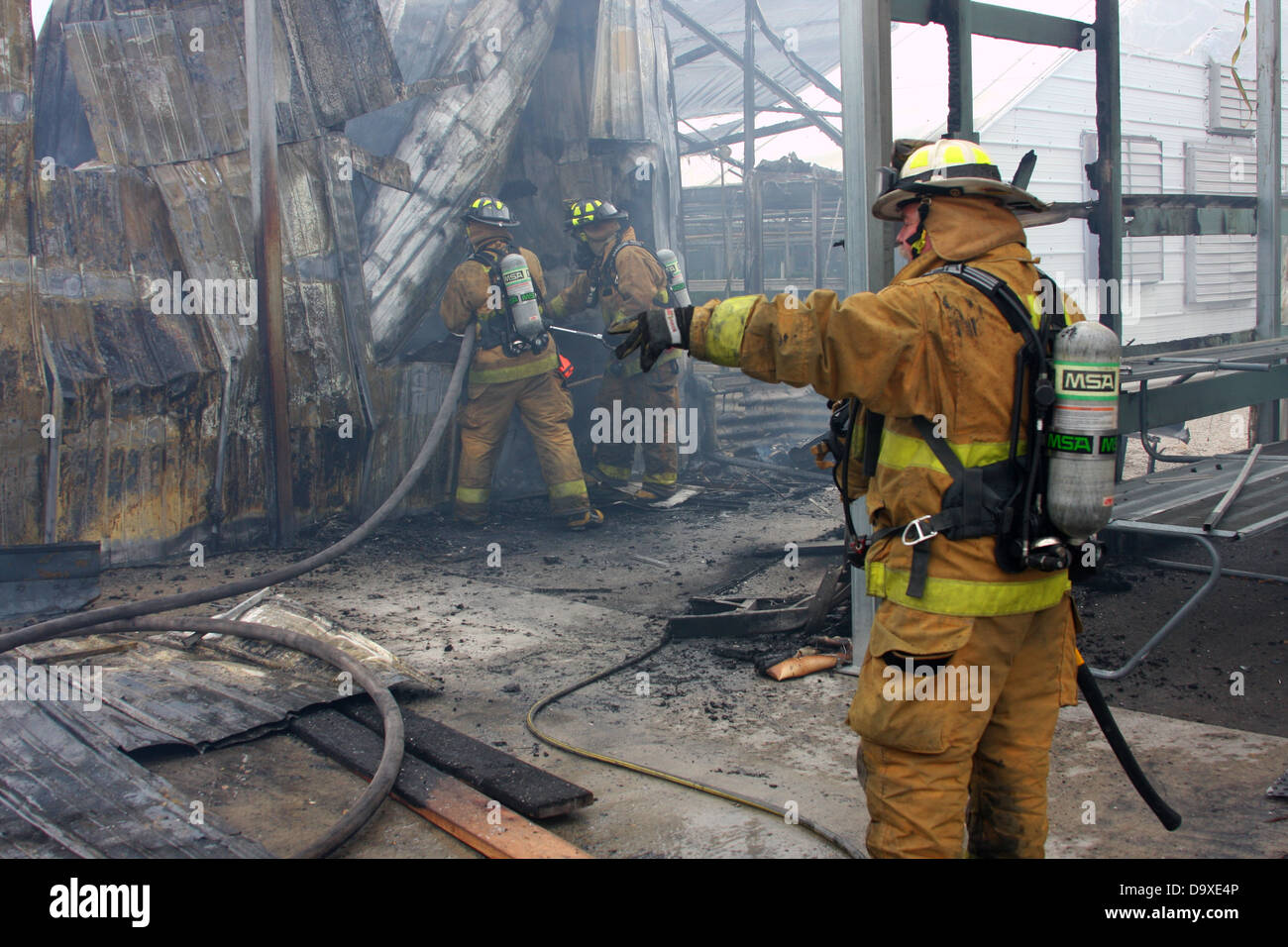 A chief giving directions as two firefighters extinguishing a fire ...