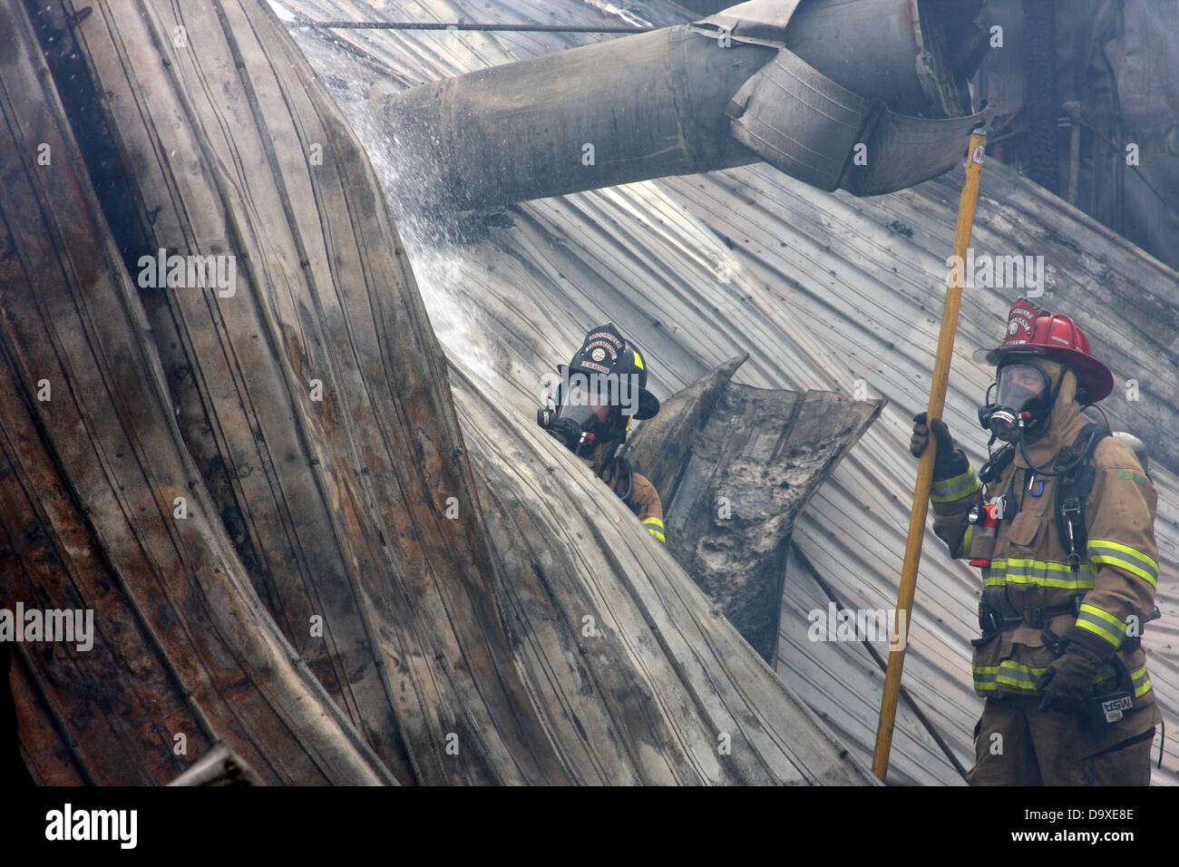 Two firefighters extinuishing a fire in a sheet metal building in ...