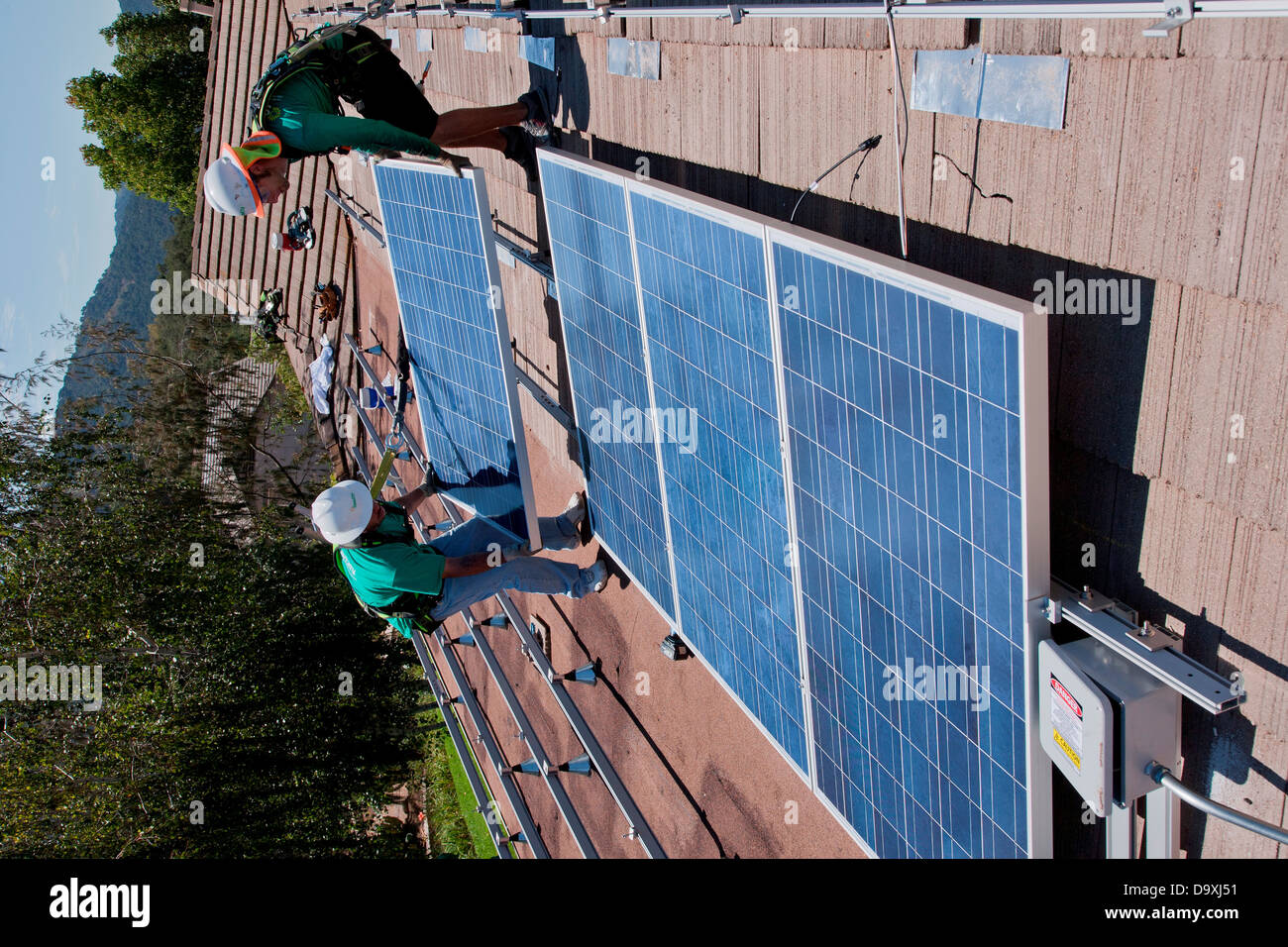 Two male solar workers install solar panels on home in Oak View ...