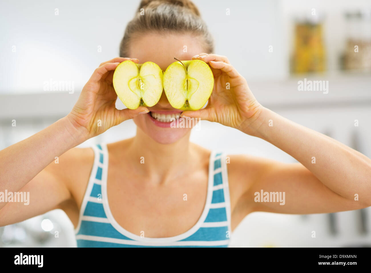 Happy young woman holding two slices of apple in front of eyes Stock ...