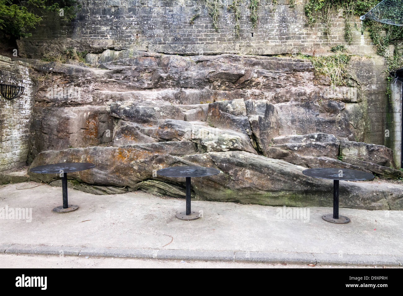 Three outdoor black-painted circular metal tables fixed to the floor at ...