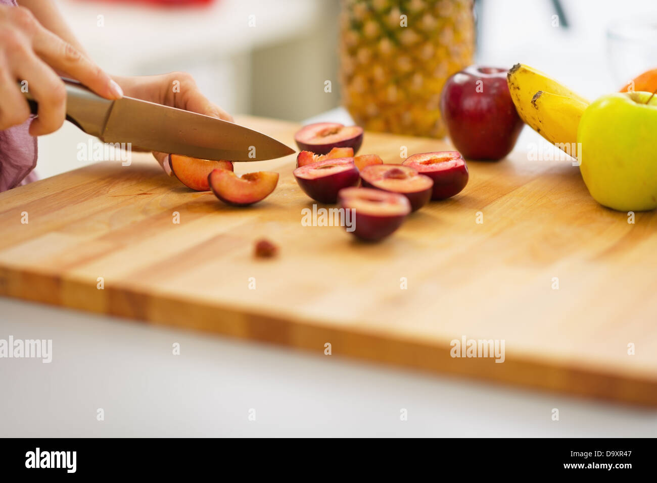 Closeup on young woman cutting plums Stock Photo - Alamy